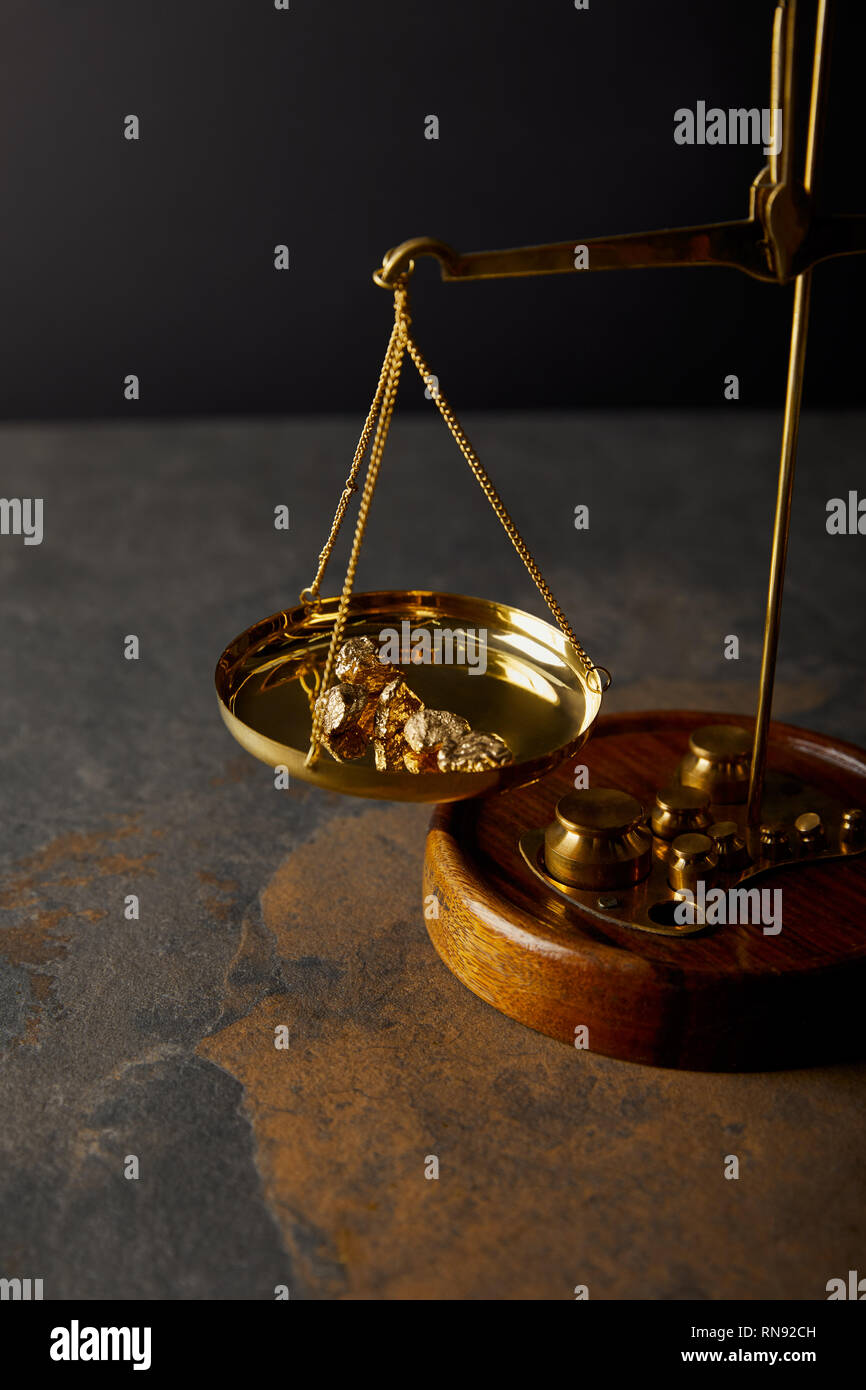 golden stones on scales on marble table and black background Stock ...