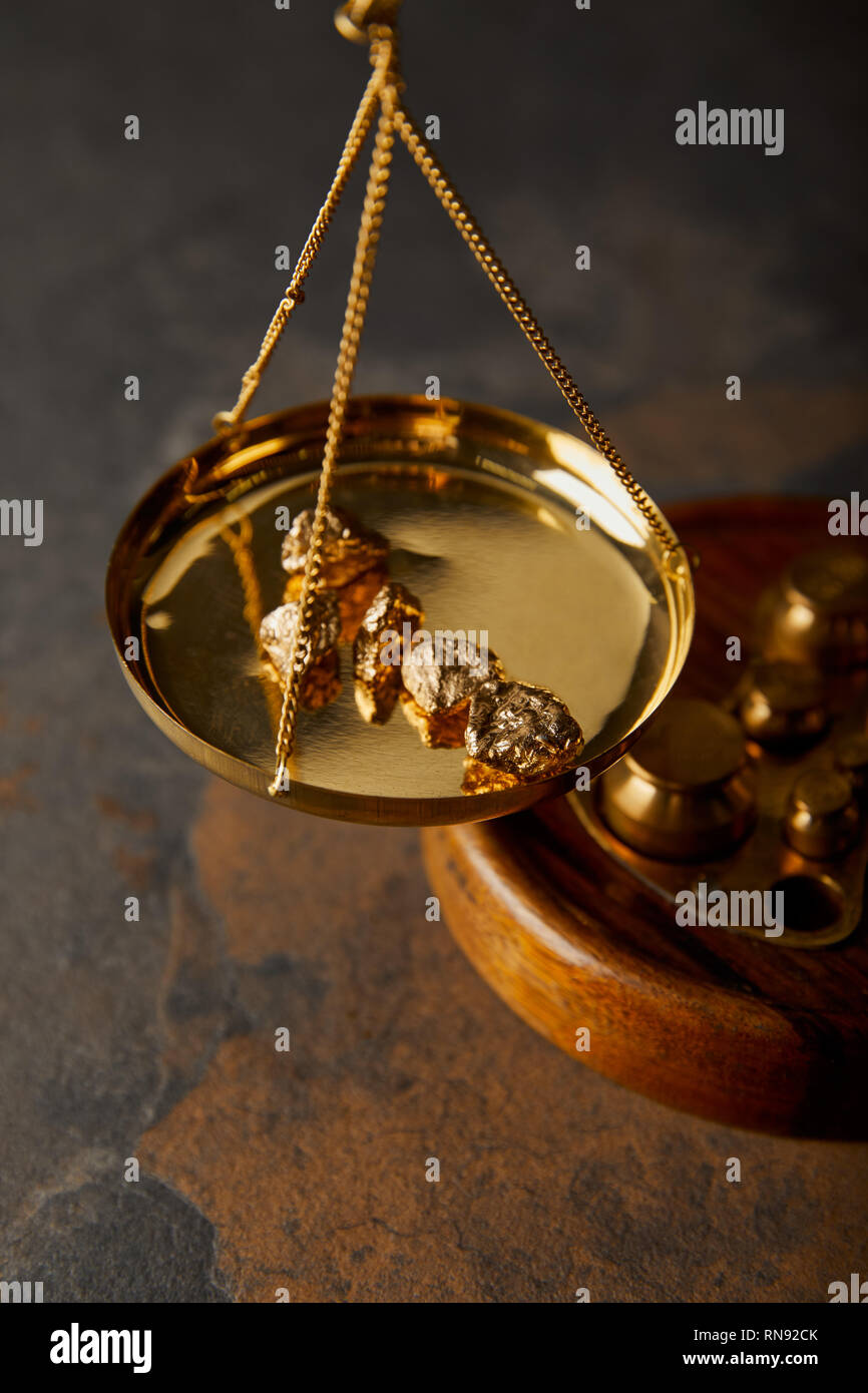 golden stones on scales on marble table Stock Photo - Alamy