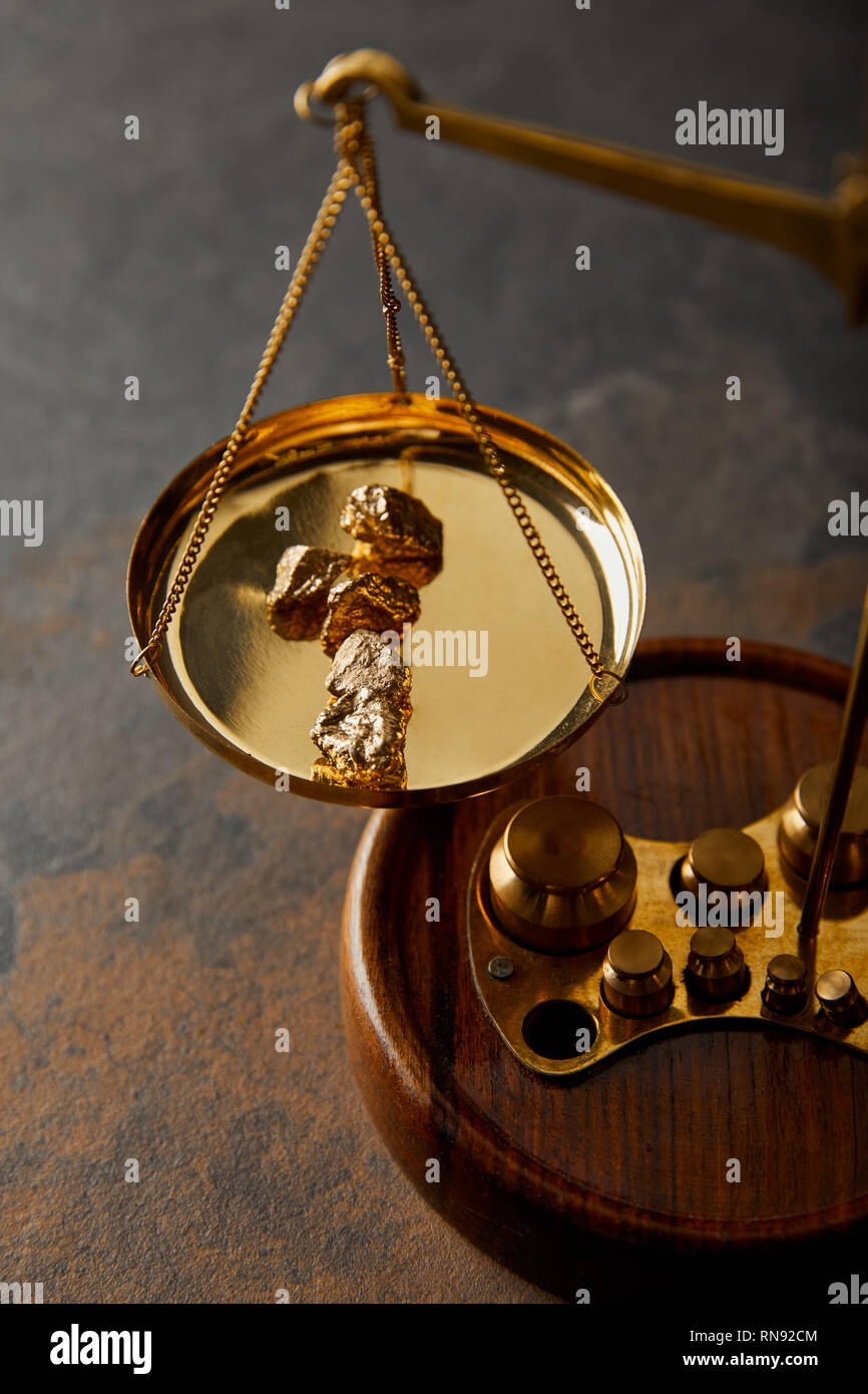 golden stones on wooden scales on marble table Stock Photo - Alamy