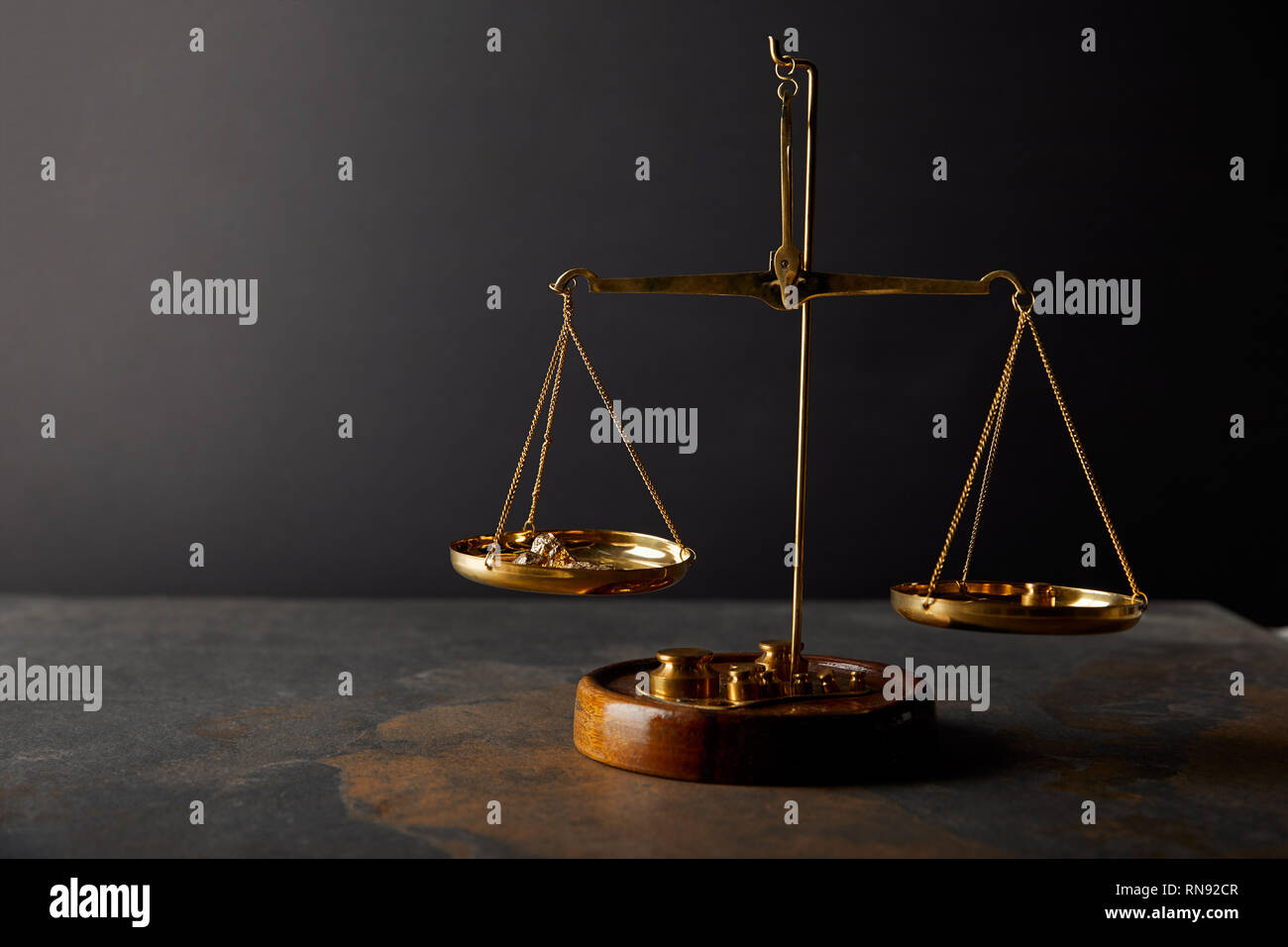 golden stones on scales on marble table and dark background Stock Photo ...