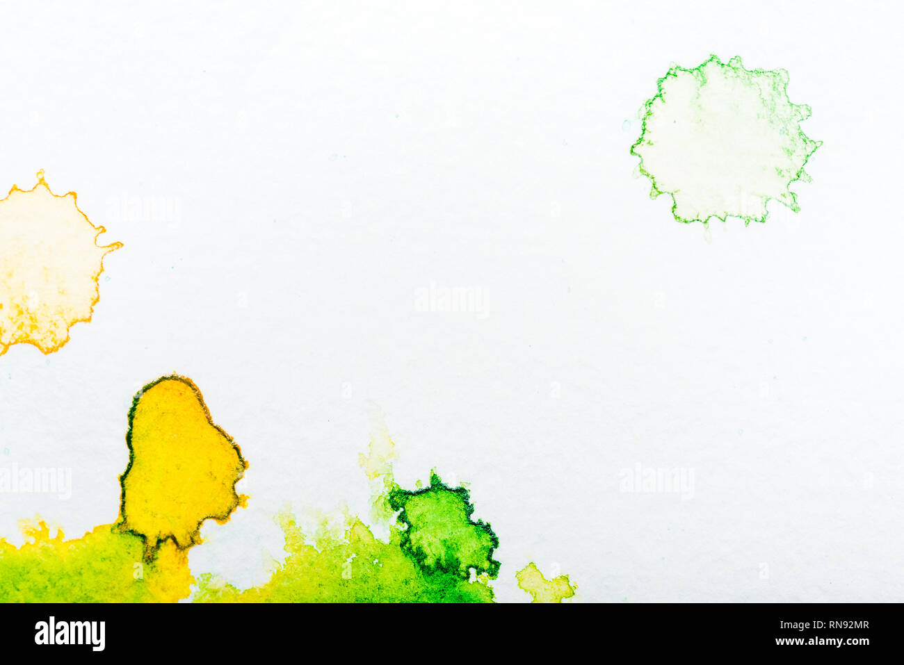 top view of yellow and green watercolor spills on white background ...