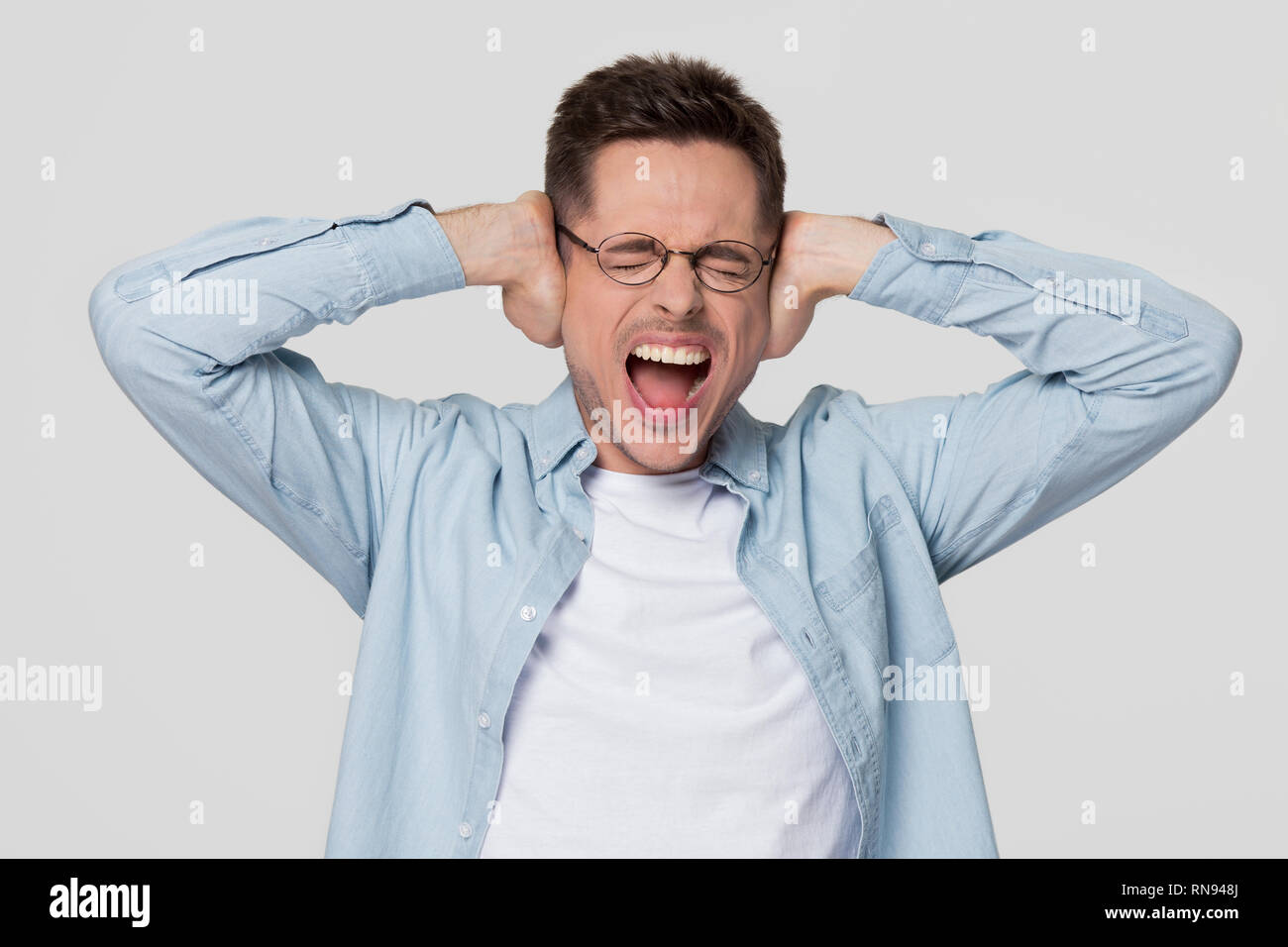 Stubborn angry young man covering his ears hearing annoying noise Stock ...