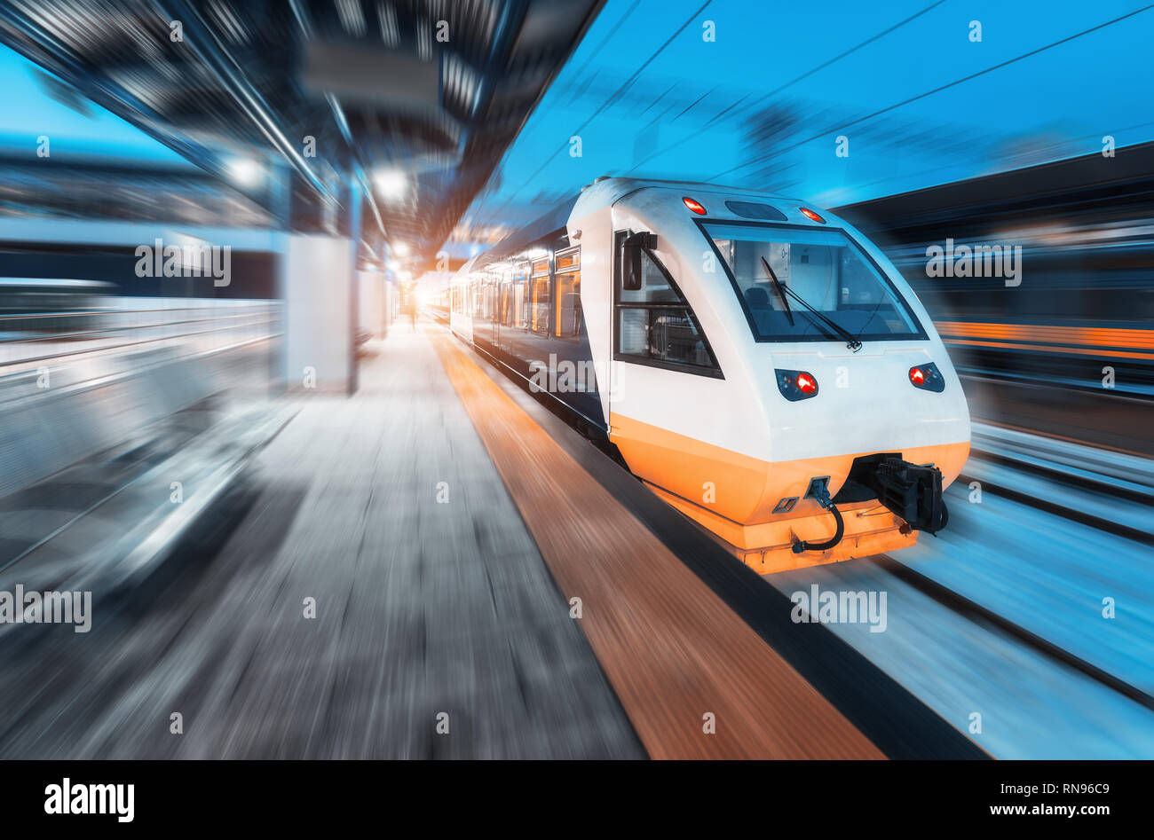 Moving train on the railway station at night. Urban landscape with ...