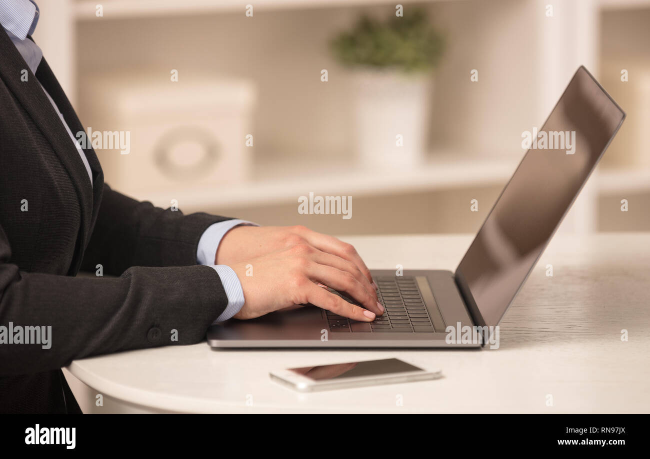 Business woman below chest working on her laptop in a cozy environment ...