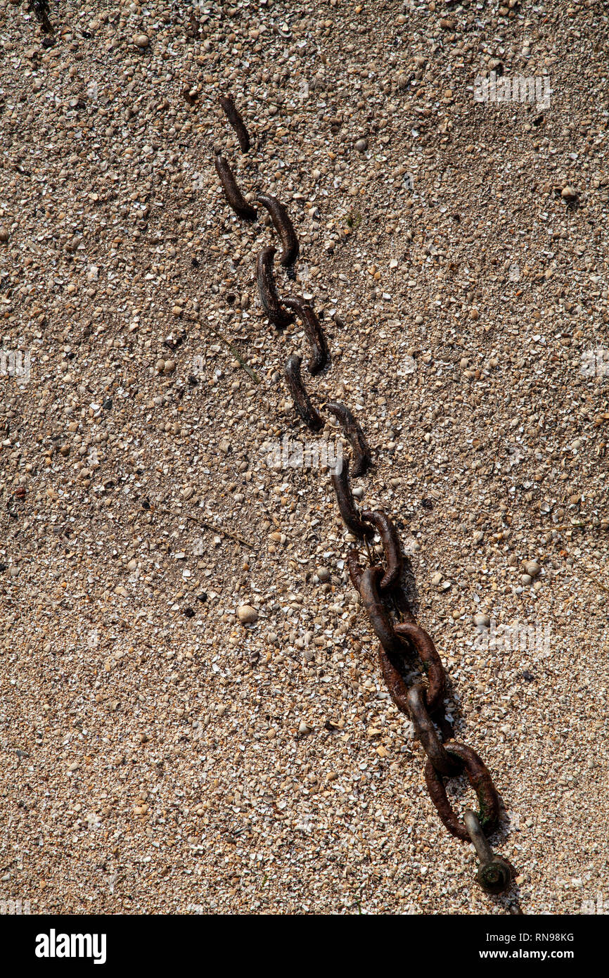 Chain partially buried in sand on the beach Stock Photo - Alamy