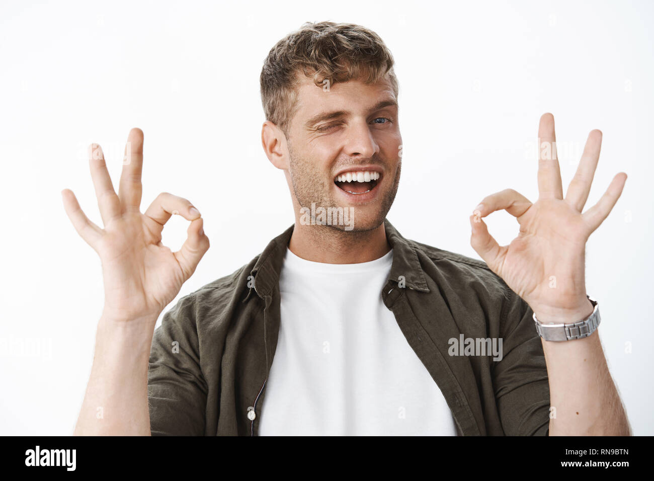 Portrat of good-looking blond man showing okay gesture and winking with ...