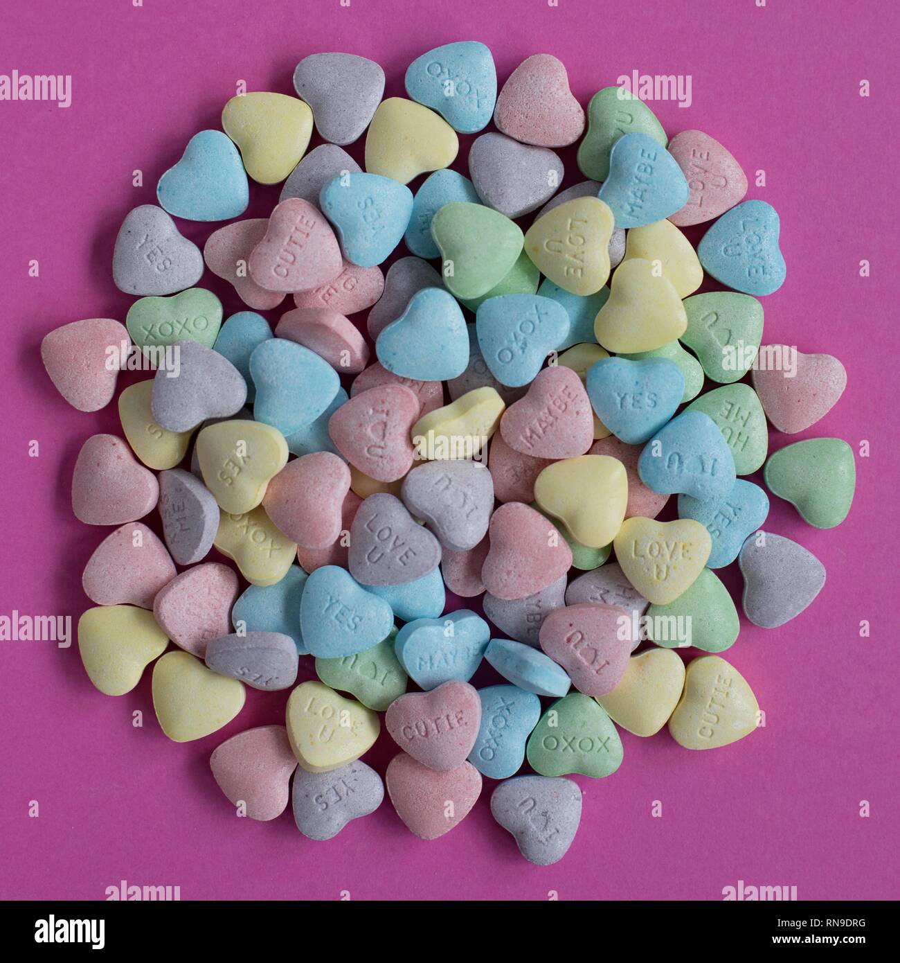 Candy conversation hearts on a plain pink background Stock Photo - Alamy