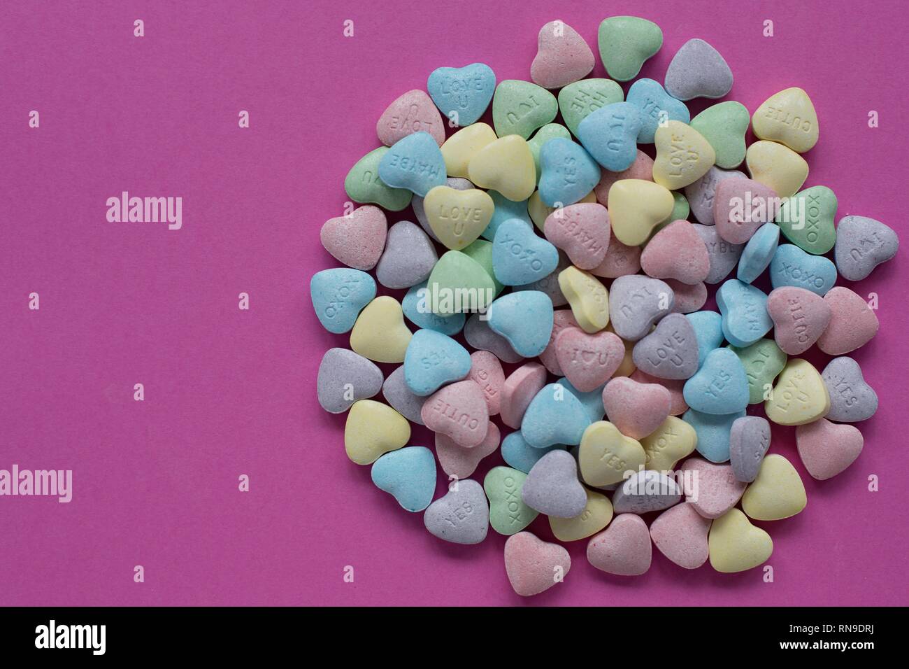 Candy conversation hearts on a plain pink background Stock Photo - Alamy