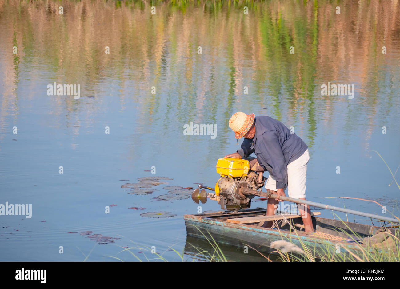 Old boatman brought the small boat with motor from the shore into the ...