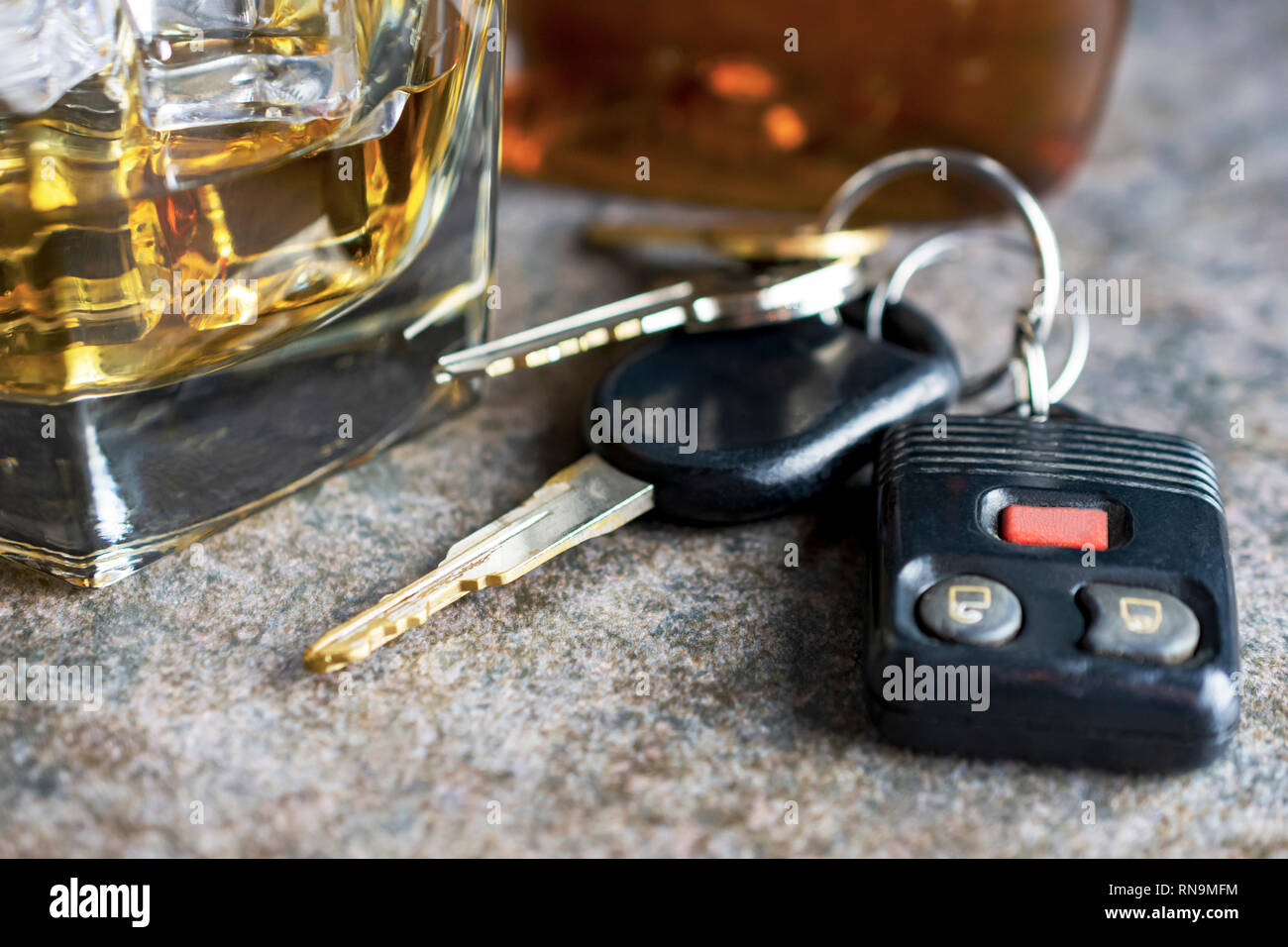 Brandy glass with keys and nearly empty bottle in background. Close up ...