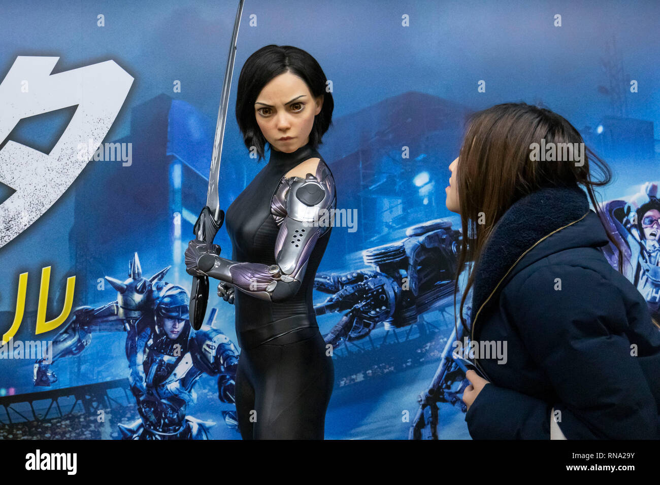 A woman looks at a life-size statue of Alita in a corridor of Shinjuku ...
