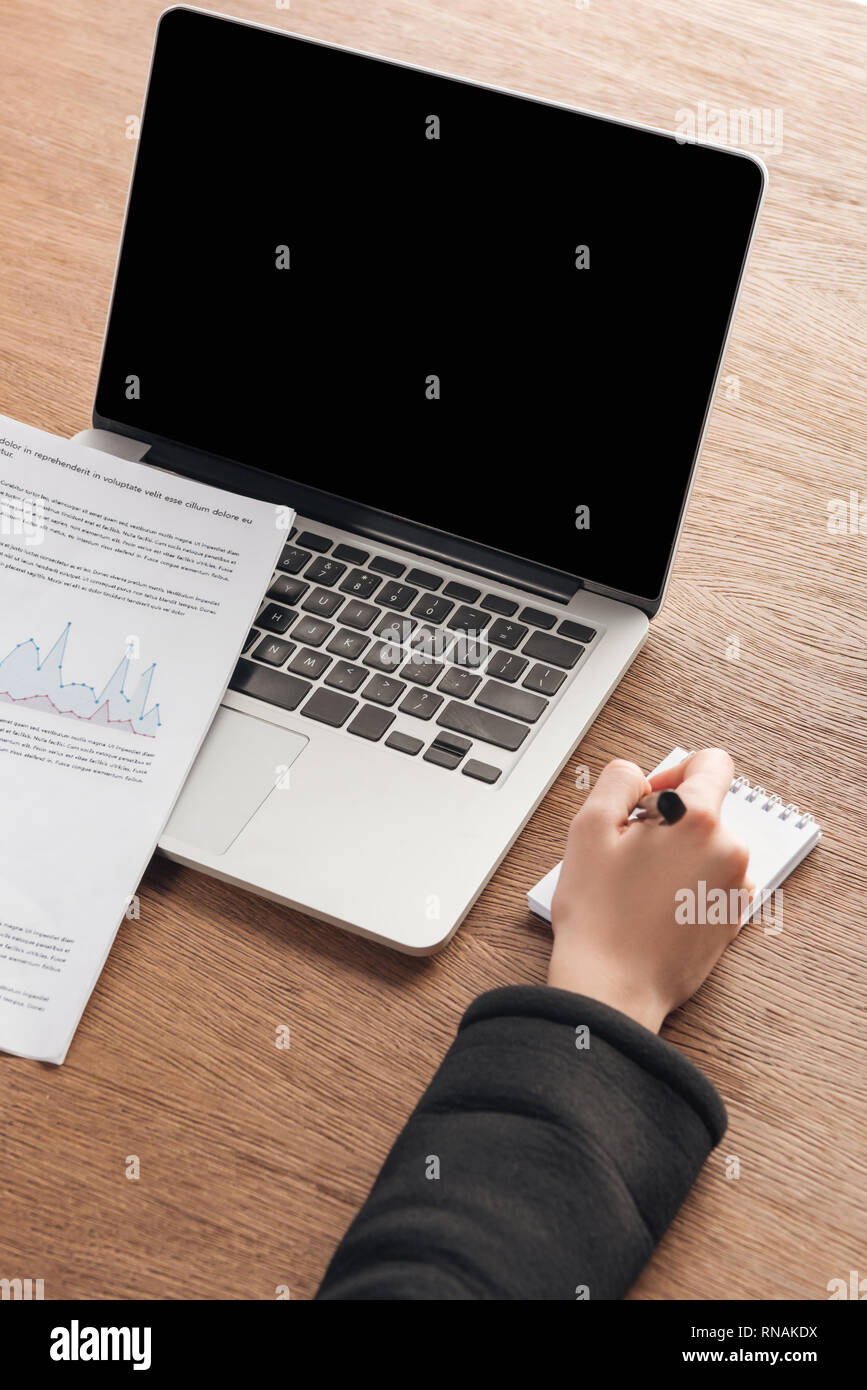 Partial view of woman writing in notebook at workplace Stock Photo - Alamy