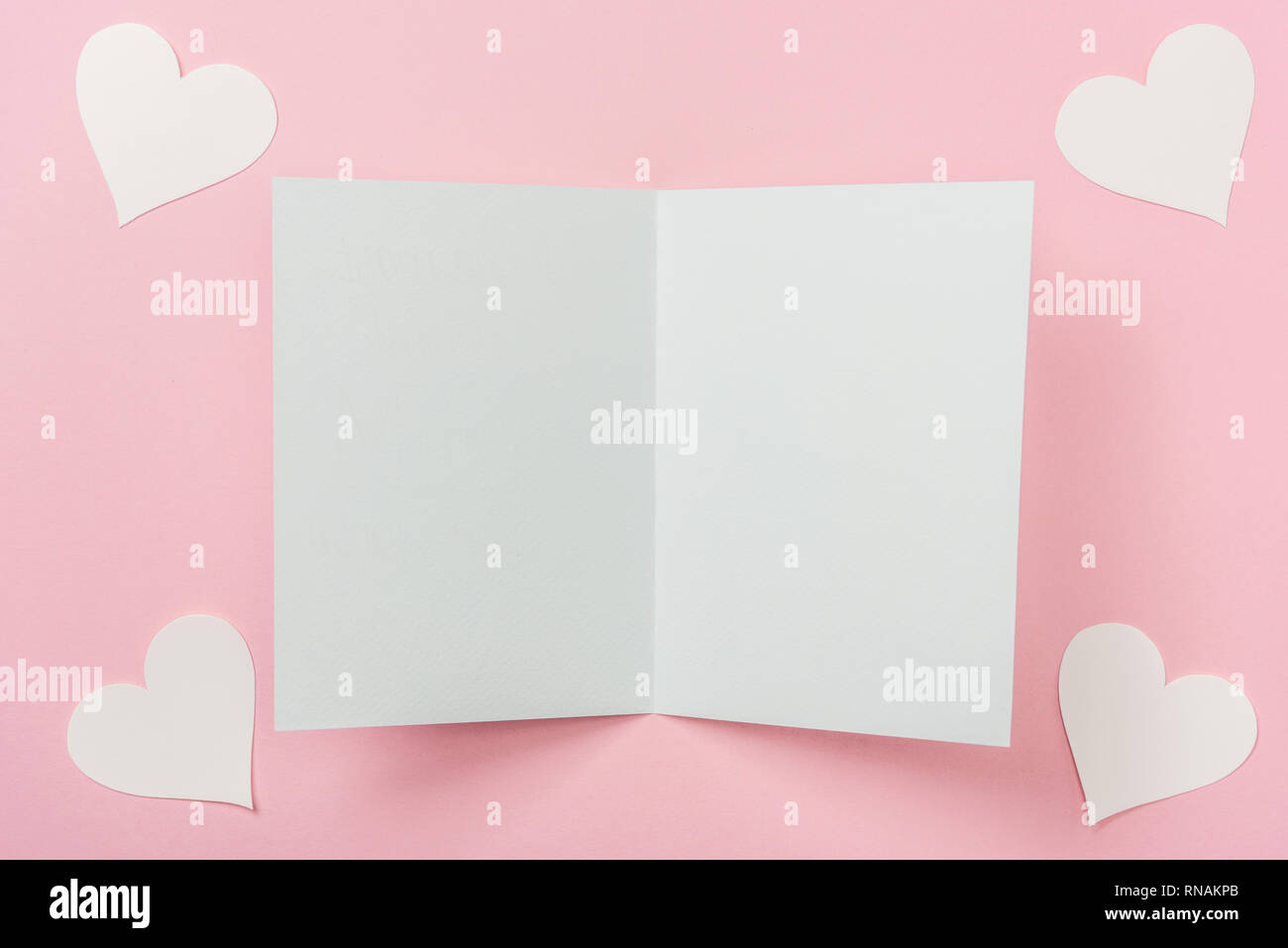 blank greeting card and white paper hearts on pink background Stock ...