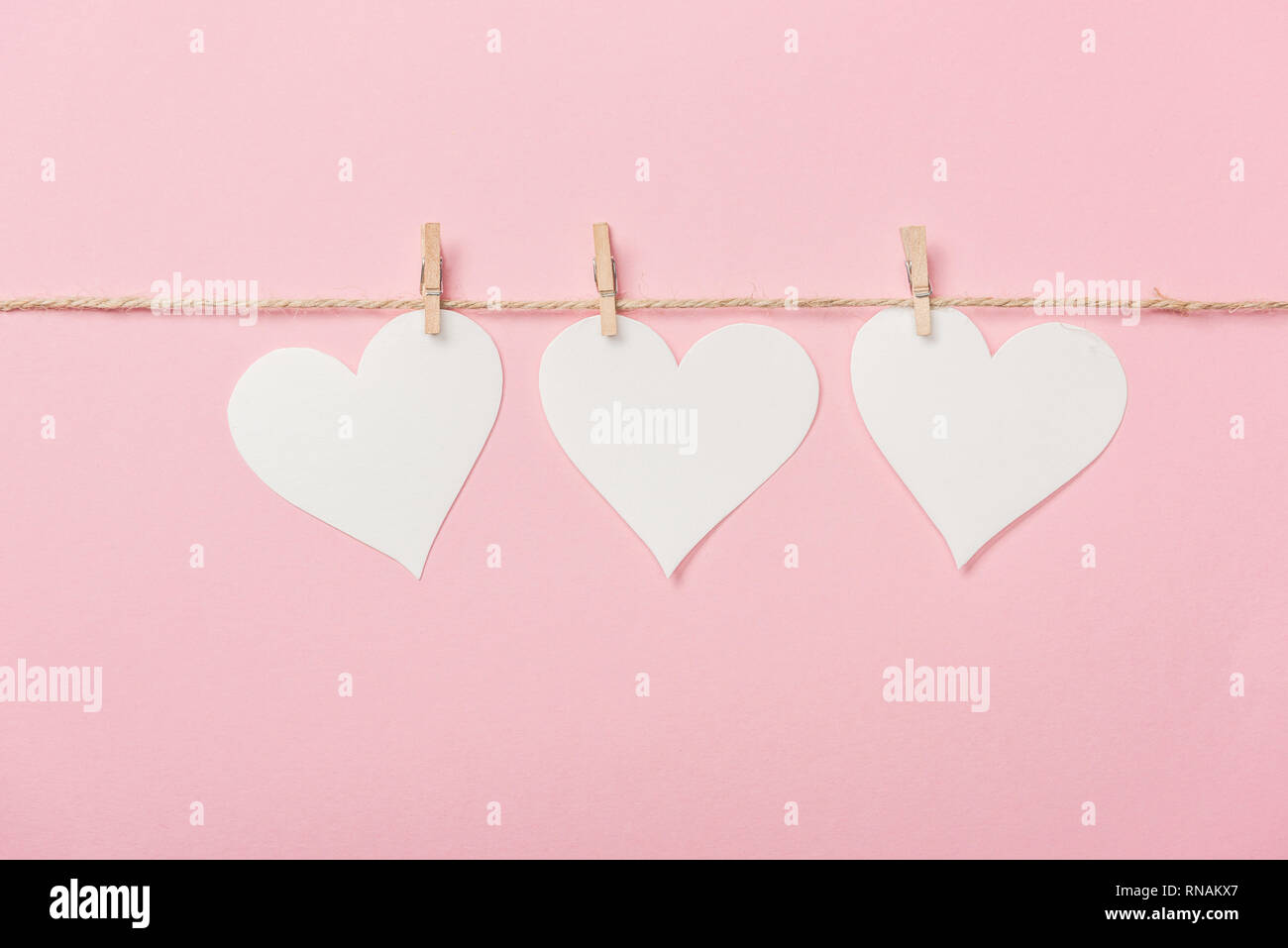 white paper hearts with coarse thread on pink background Stock Photo ...