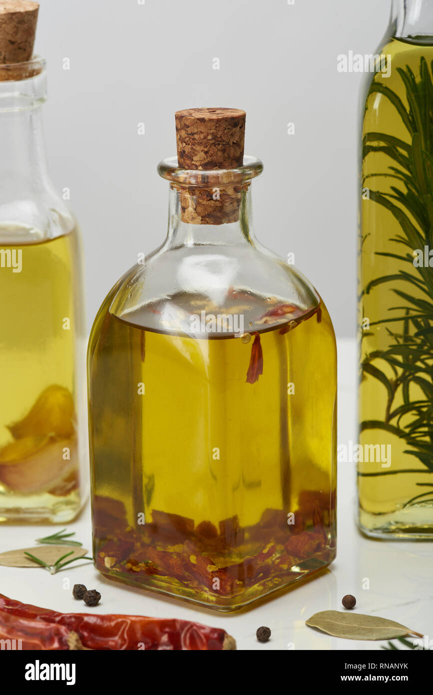 various bottles of oil flavored with different spices and rosemary on ...