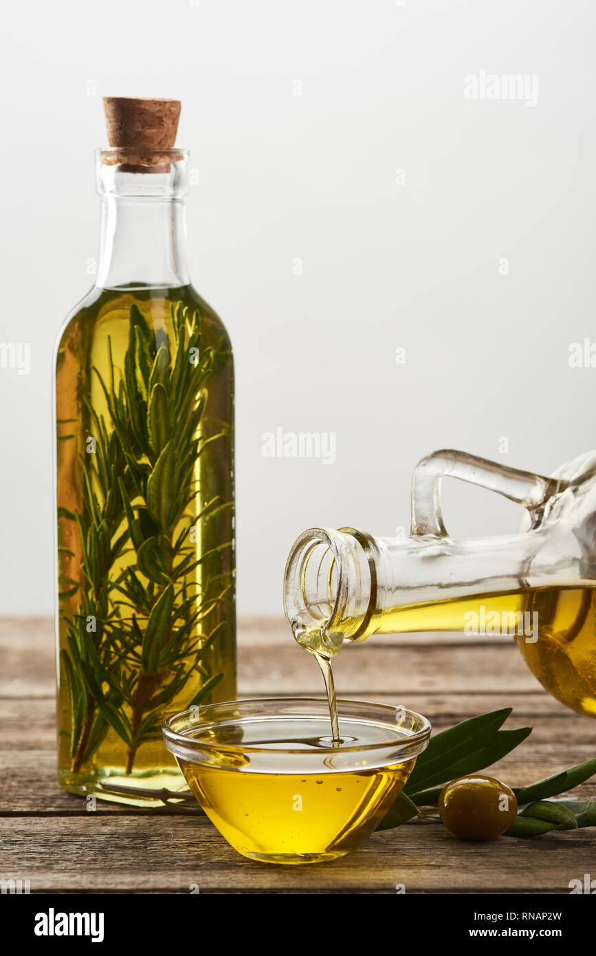 pouring olive oil from bottle into glass bowl, bottle of oil flavored ...