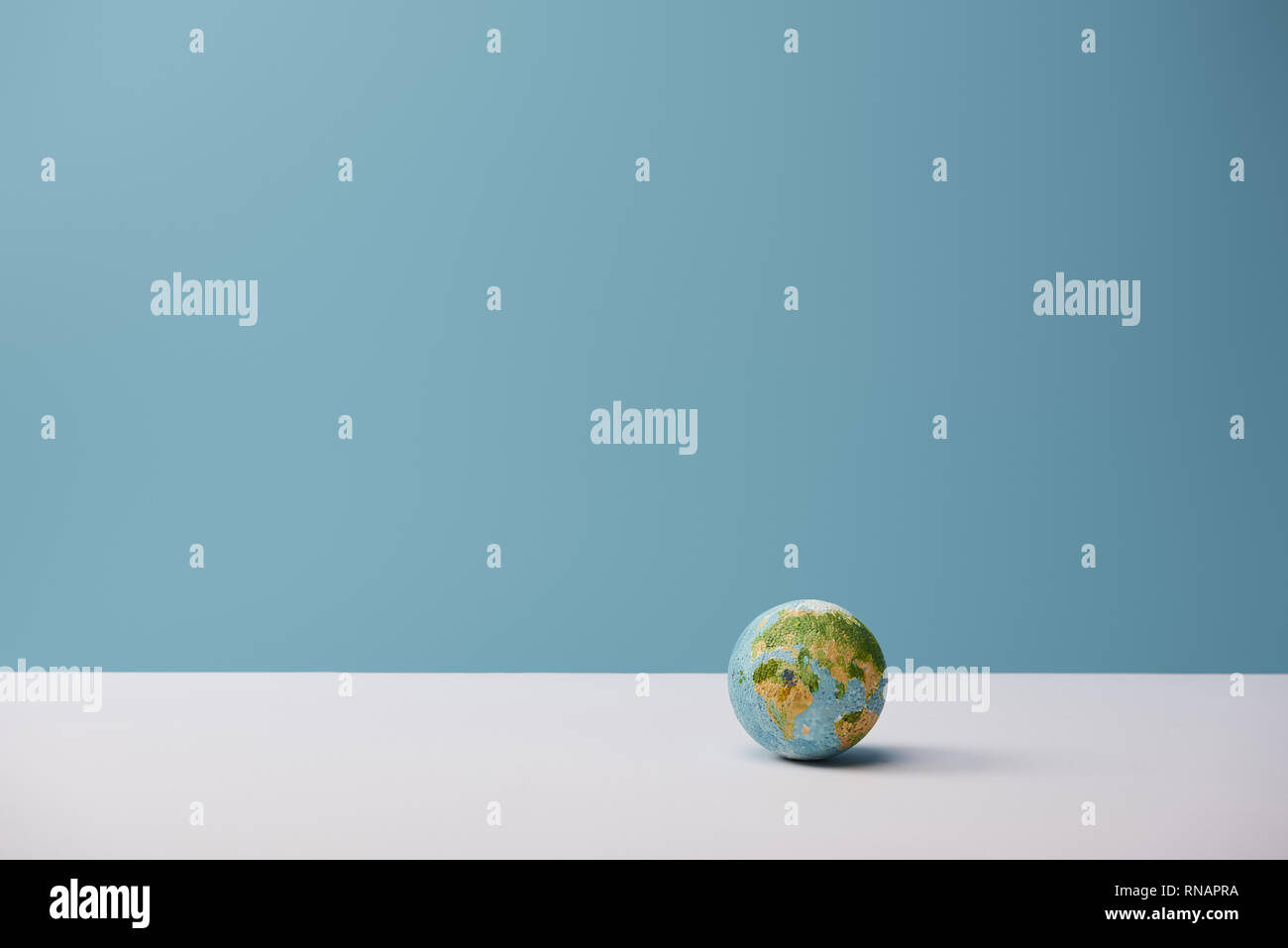 small globe on white table and blue background Stock Photo - Alamy