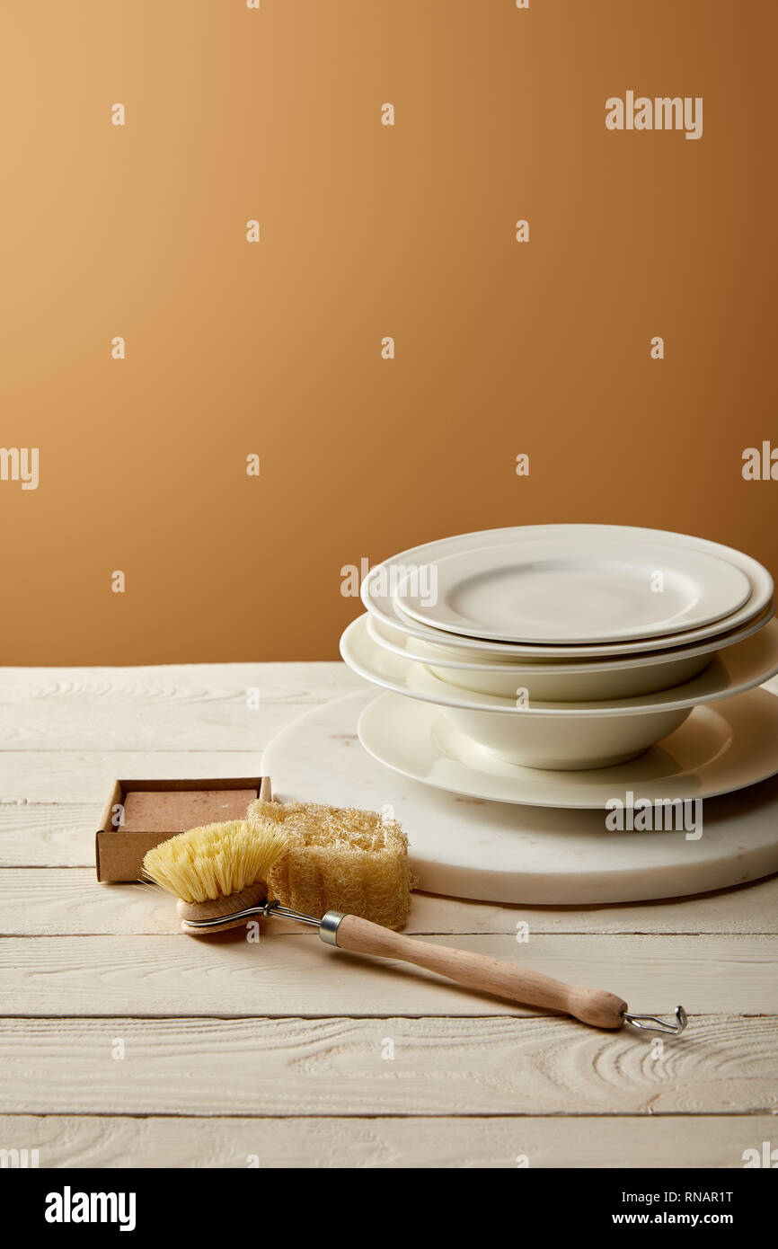 stack of plates and various cleaning items on white wooden surface ...