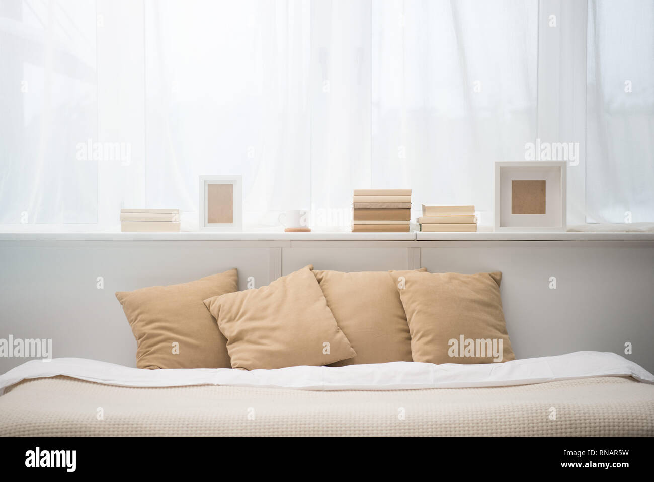 bedroom with brown pillows on bed, books, coffee cup and photo frames ...