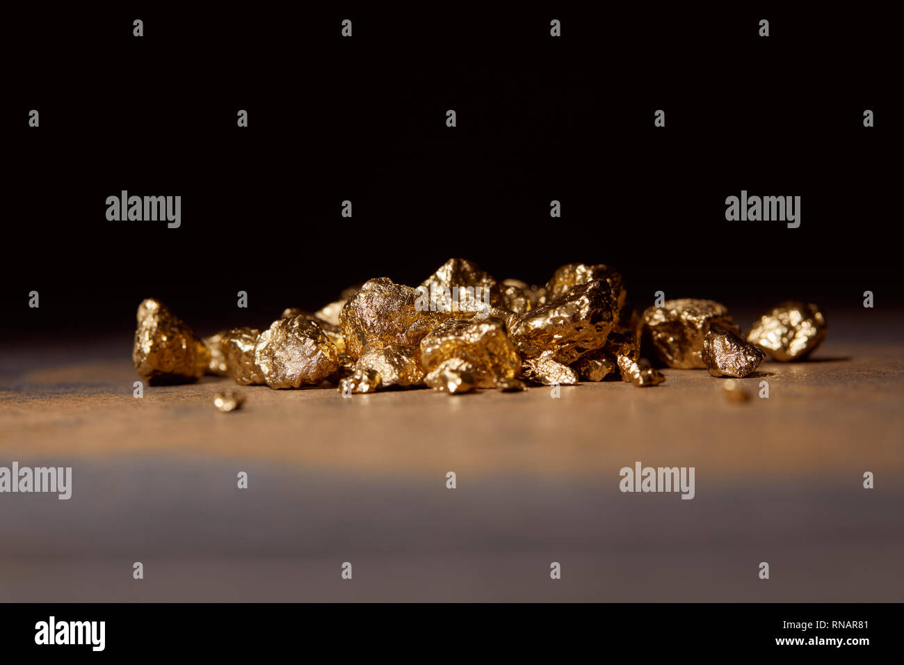 unwrought golden stones on marble table isolated on black Stock Photo ...