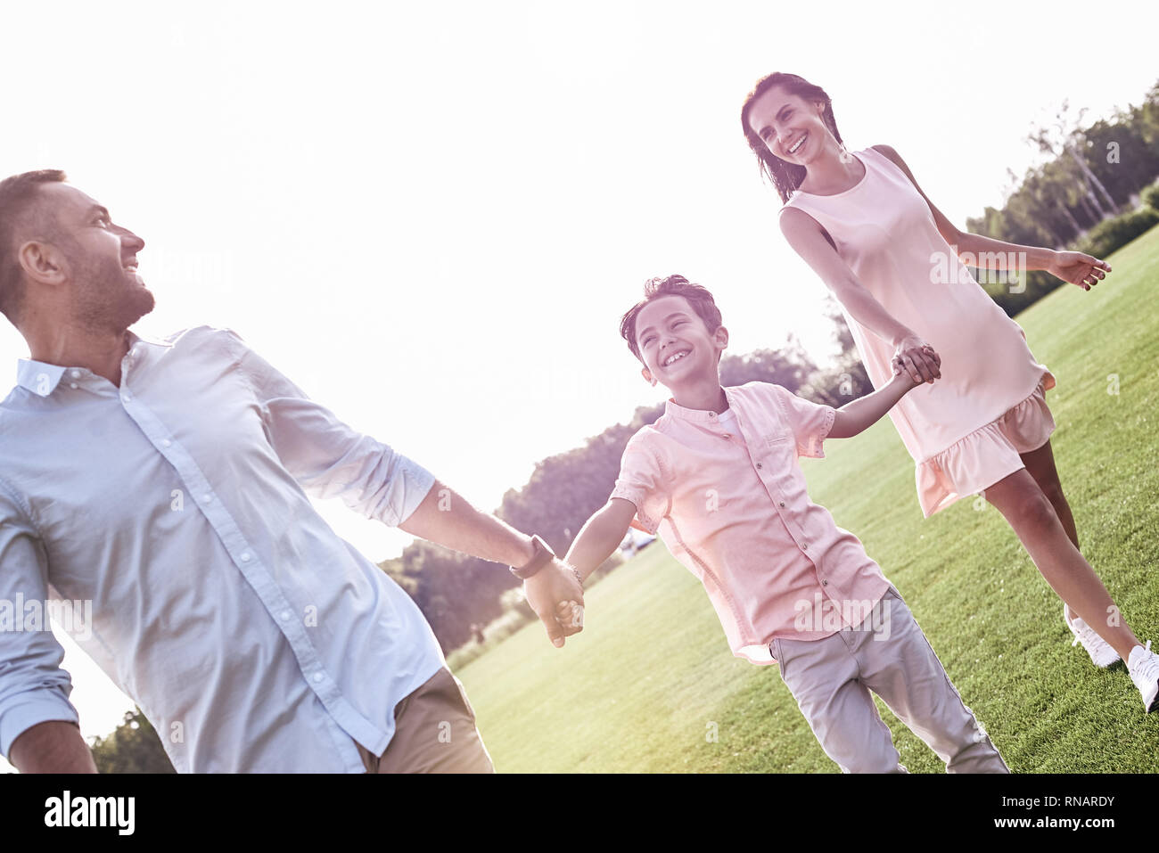 Family walk. Family of three walking on grassy field laughing happy ...