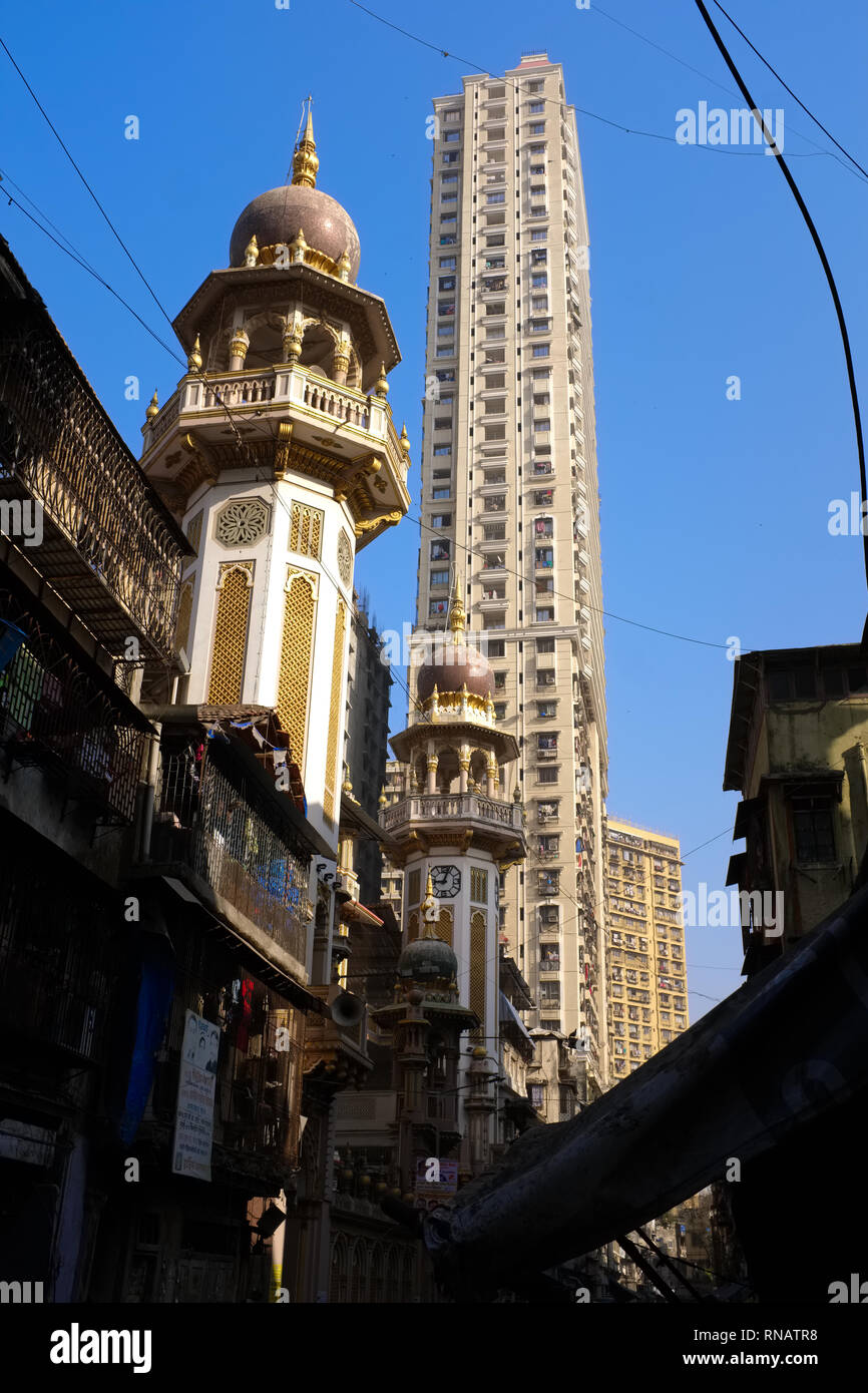 A modern highrise apartment building towers over a mosque in Muslim ...