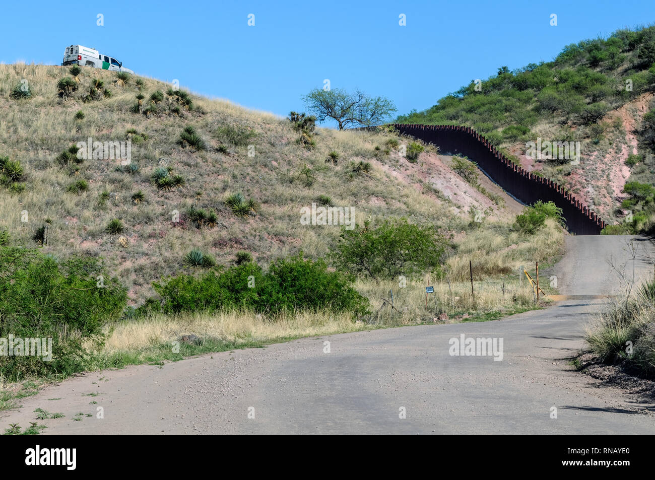 US border fence on Mexico boundary, Border Patrol vehicle parked to ...