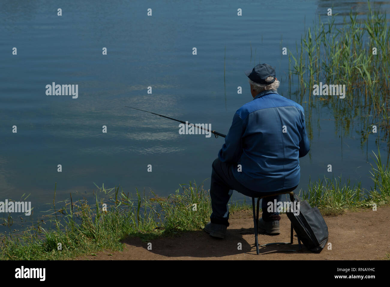 fisherman with fishing rod catching fish, sitting riverside Stock Photo ...