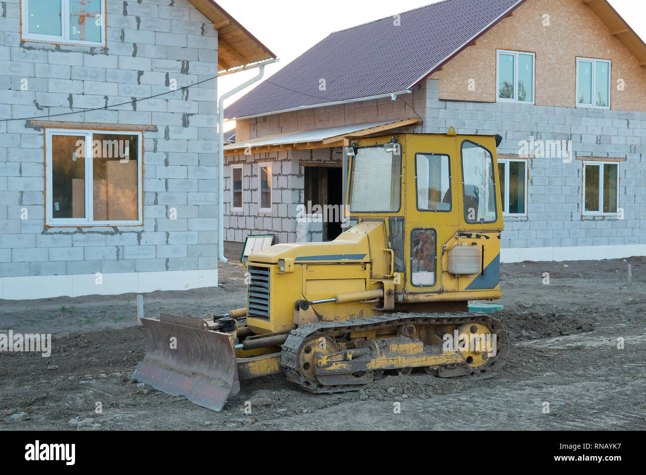 Yellow crawler bulldozer on the background of houses under construction ...