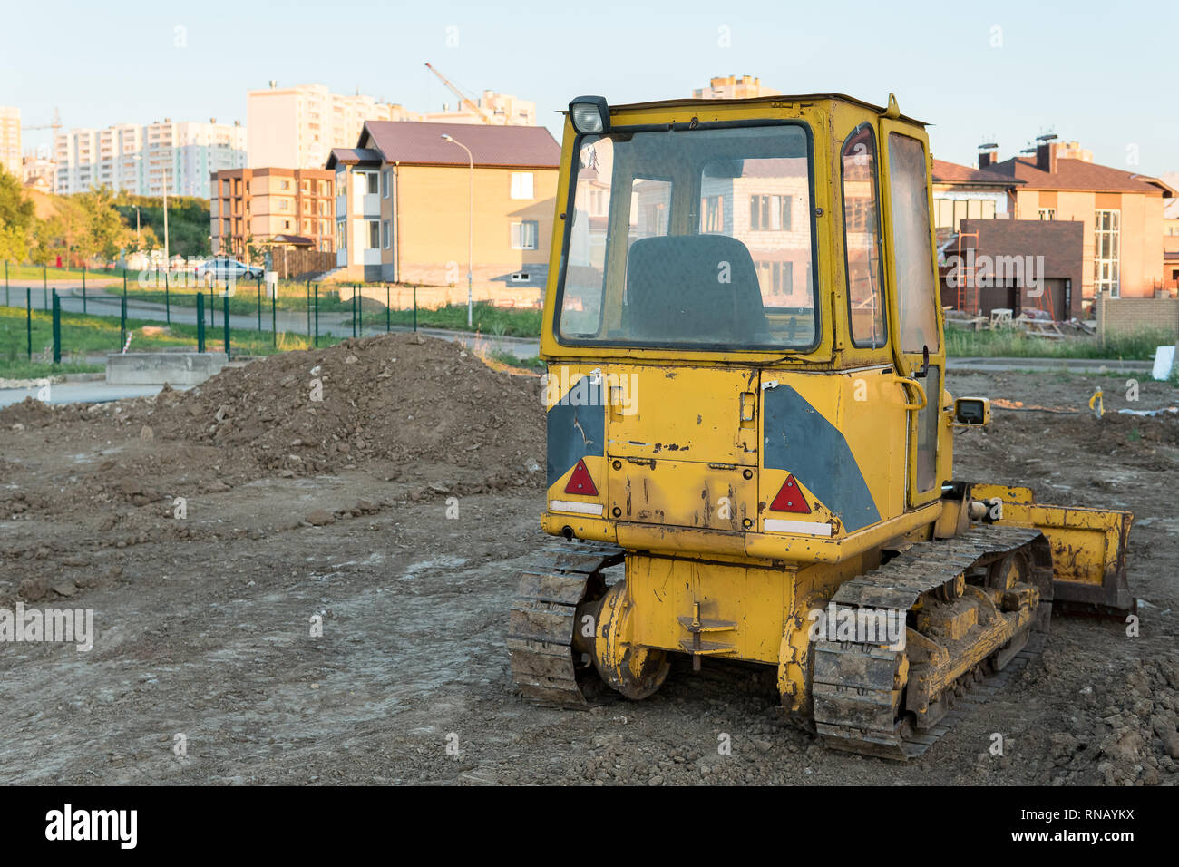 back view of small yellow bulldozer on the background of new private ...