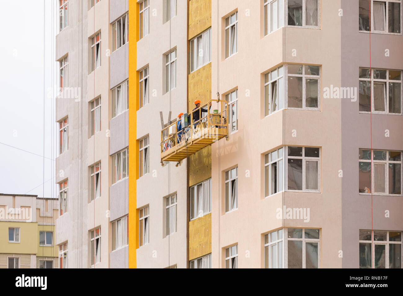 Builders paint the facade of a high-rise residential building Stock ...