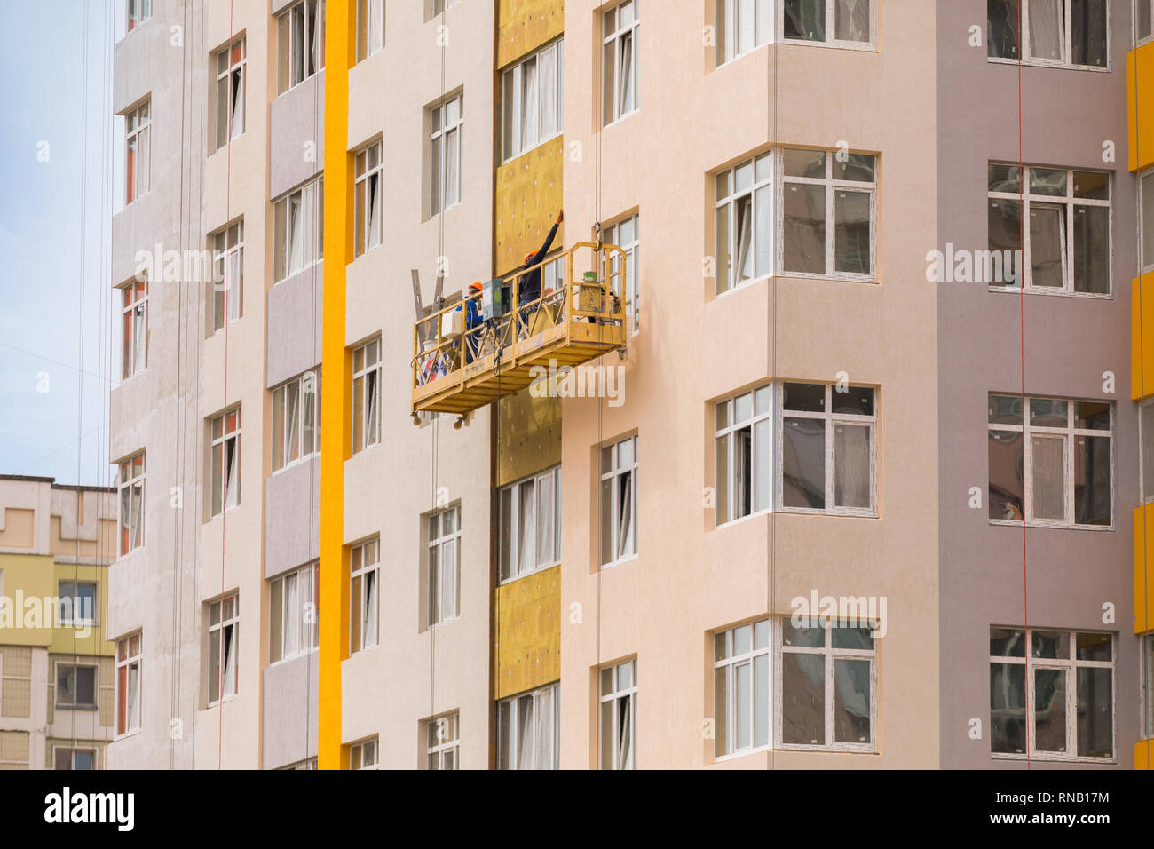 Builders paint the facade of a high-rise residential building Stock ...