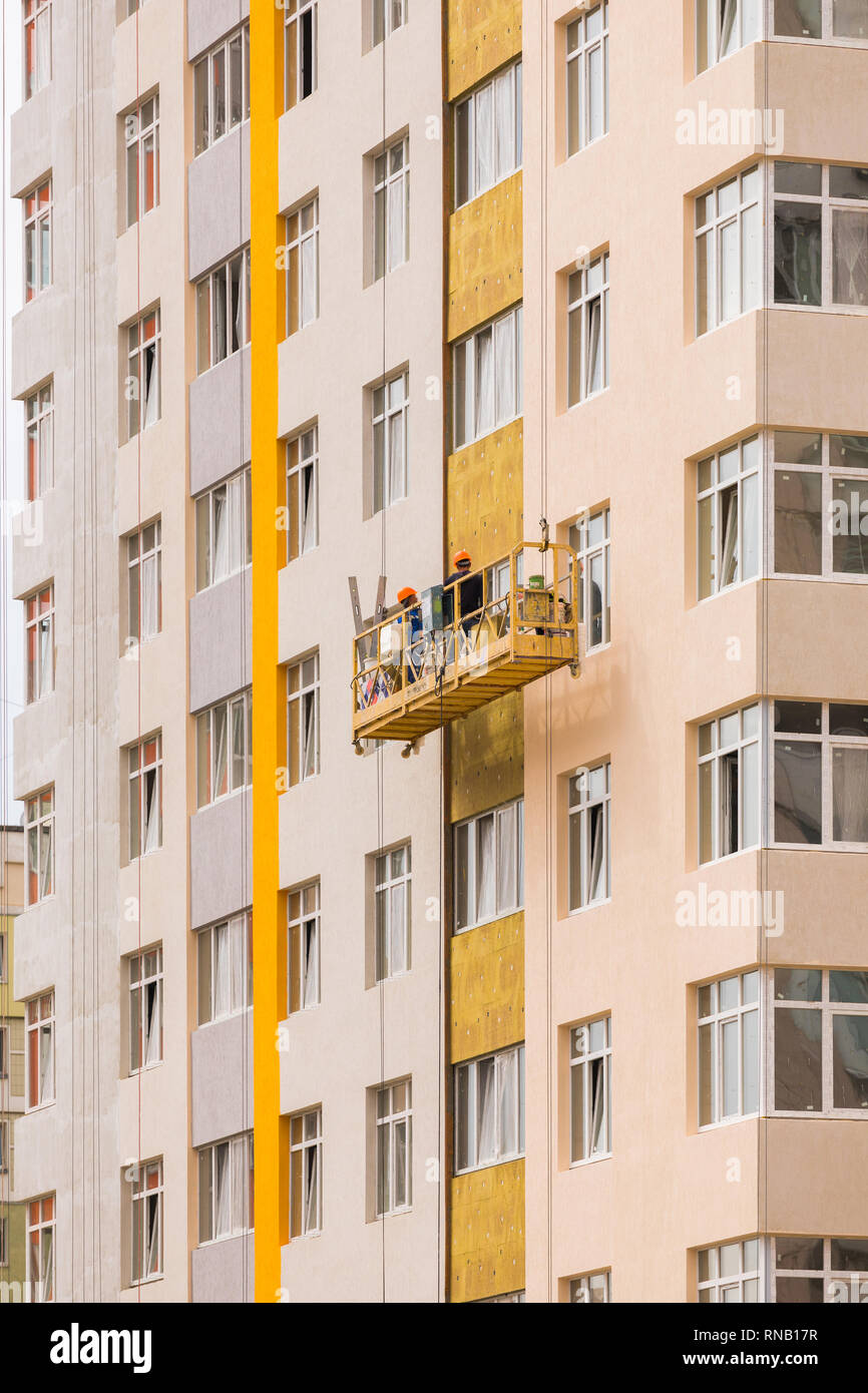 Builders paint the facade of a high-rise residential building Stock ...
