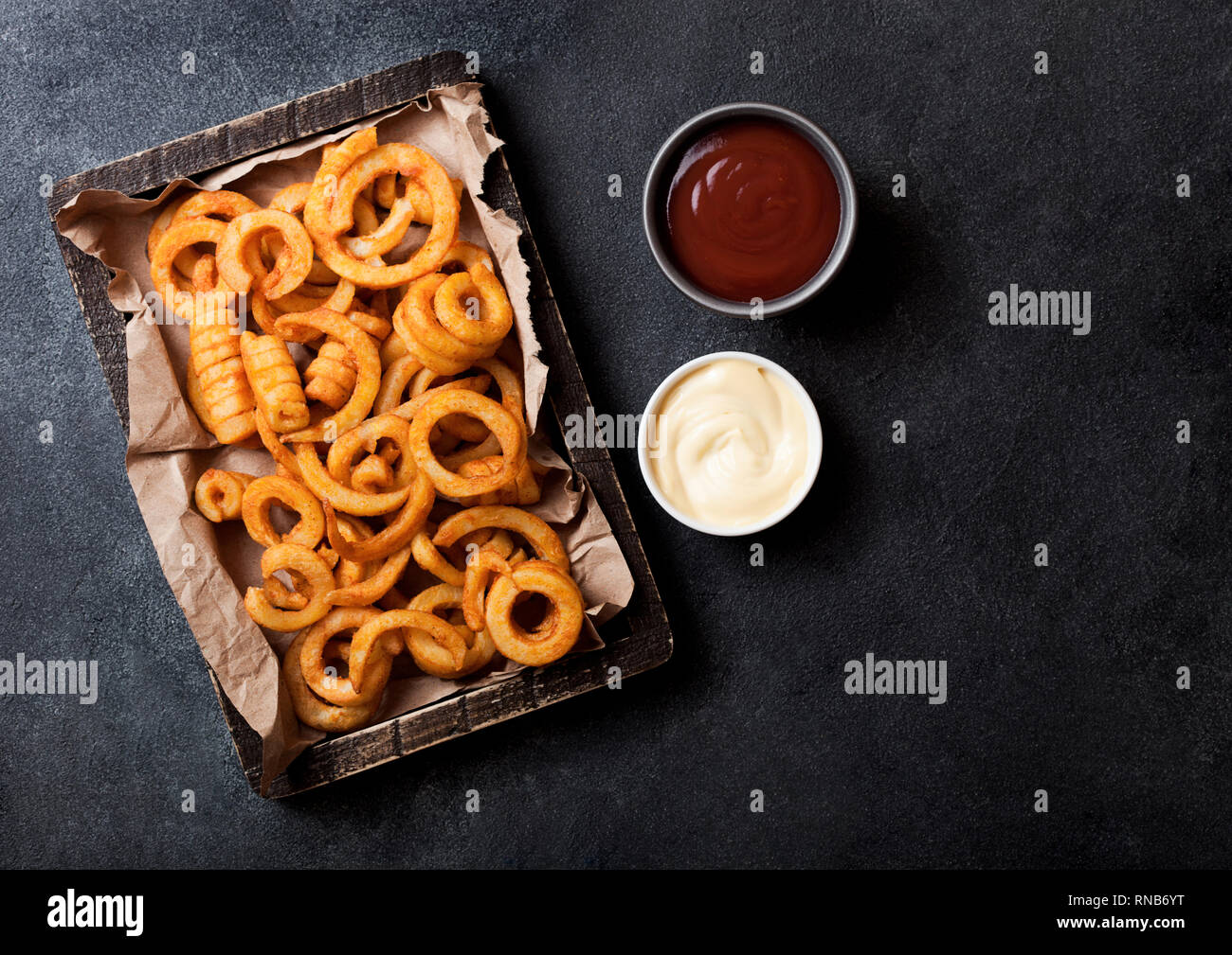 Curly fries fast food snack in wooden box with ketchup on kitchen ...