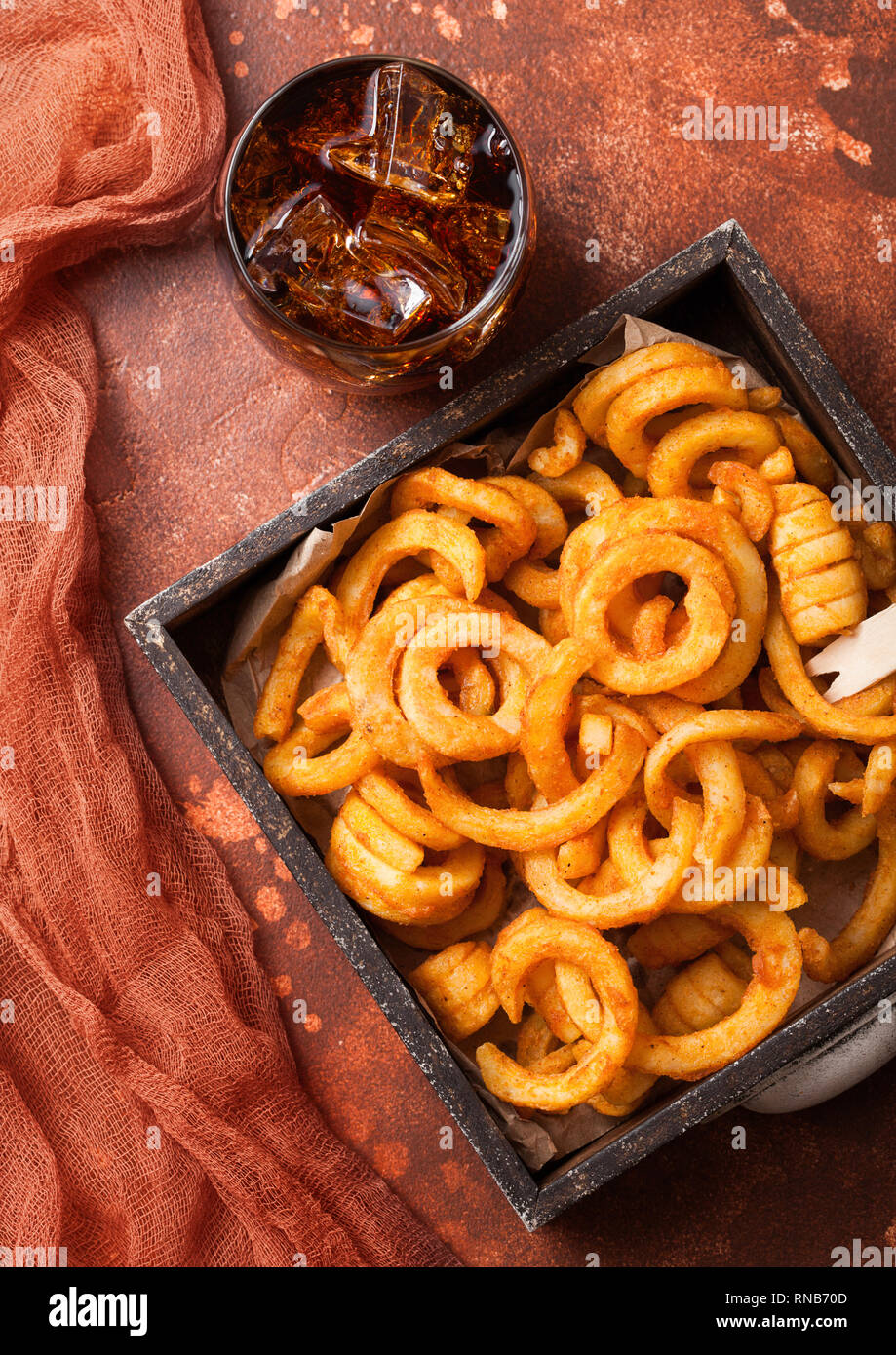 Curly fries fast food snack in wooden box with glass of cola on rusty ...