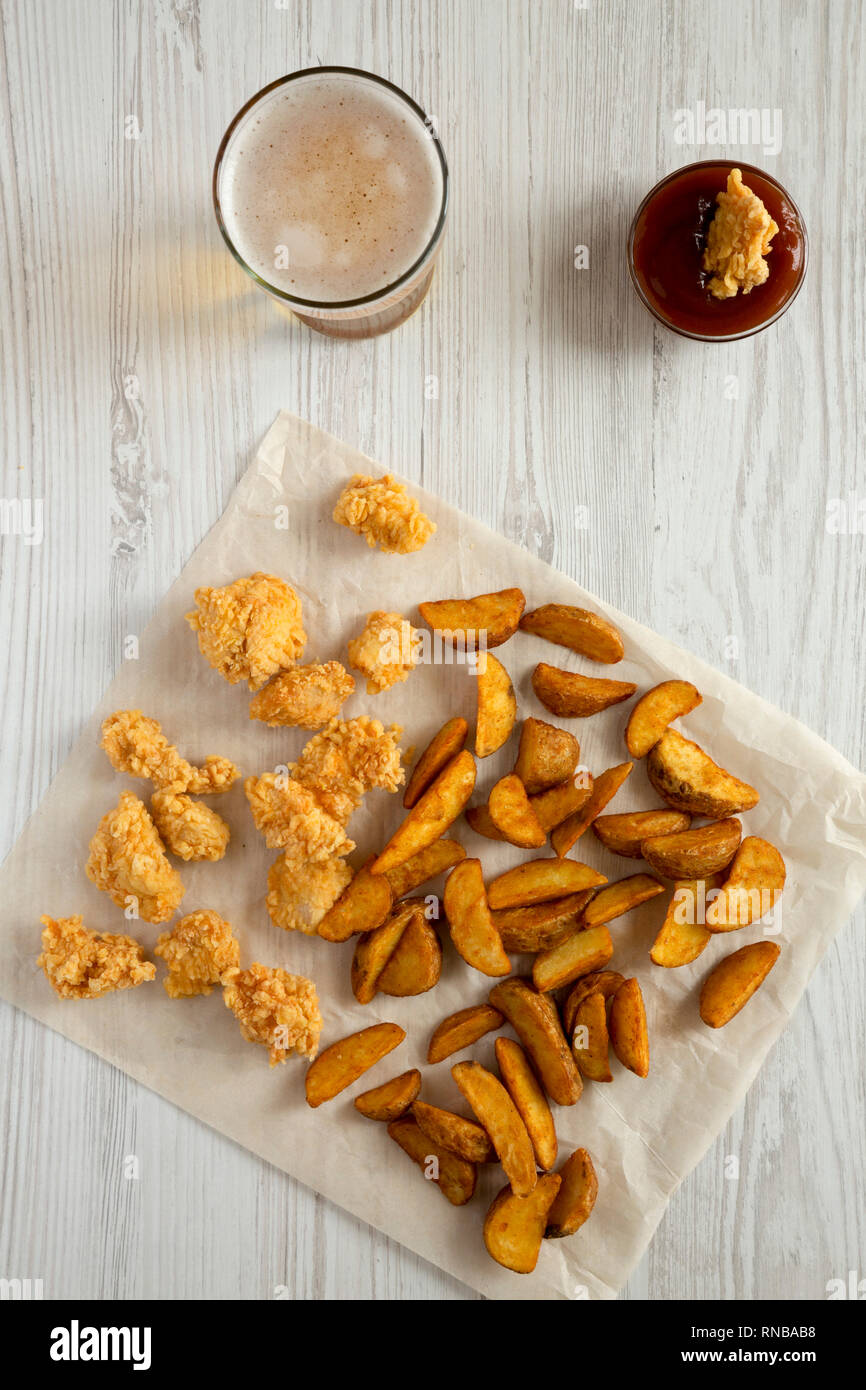 Fast food: fried potato wedges, chicken bites, beer and bbq sauce on a ...
