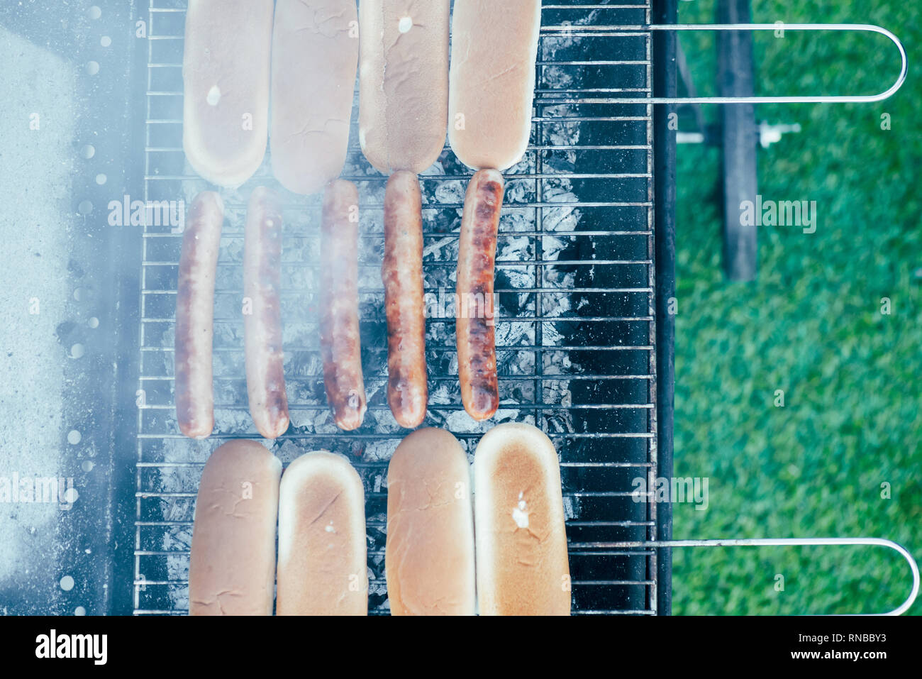 top view of tasty hot dogs grilling on bbq grill grade on green grass ...