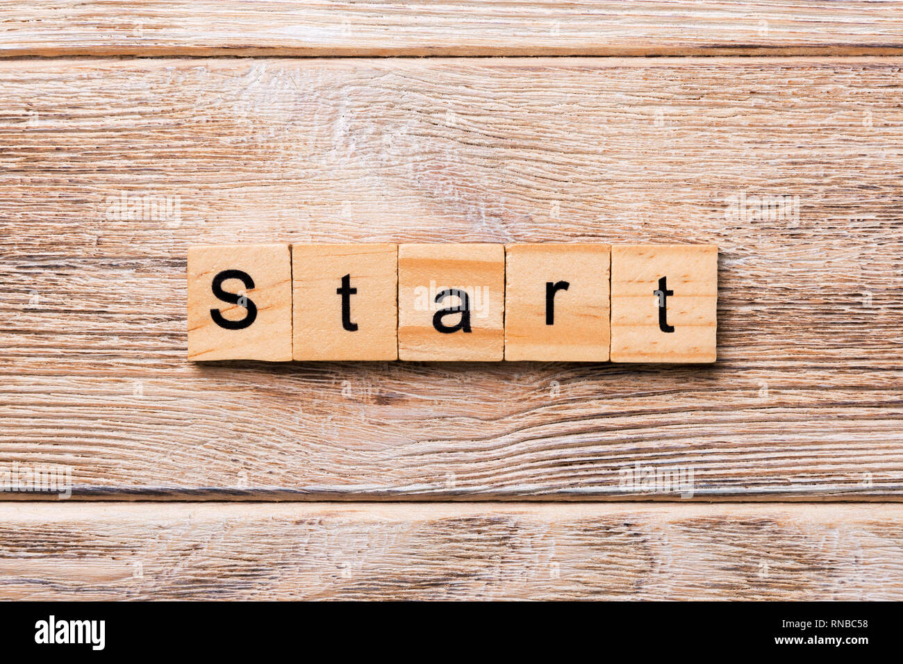 Start word written on wood block. Start text on wooden table for your ...