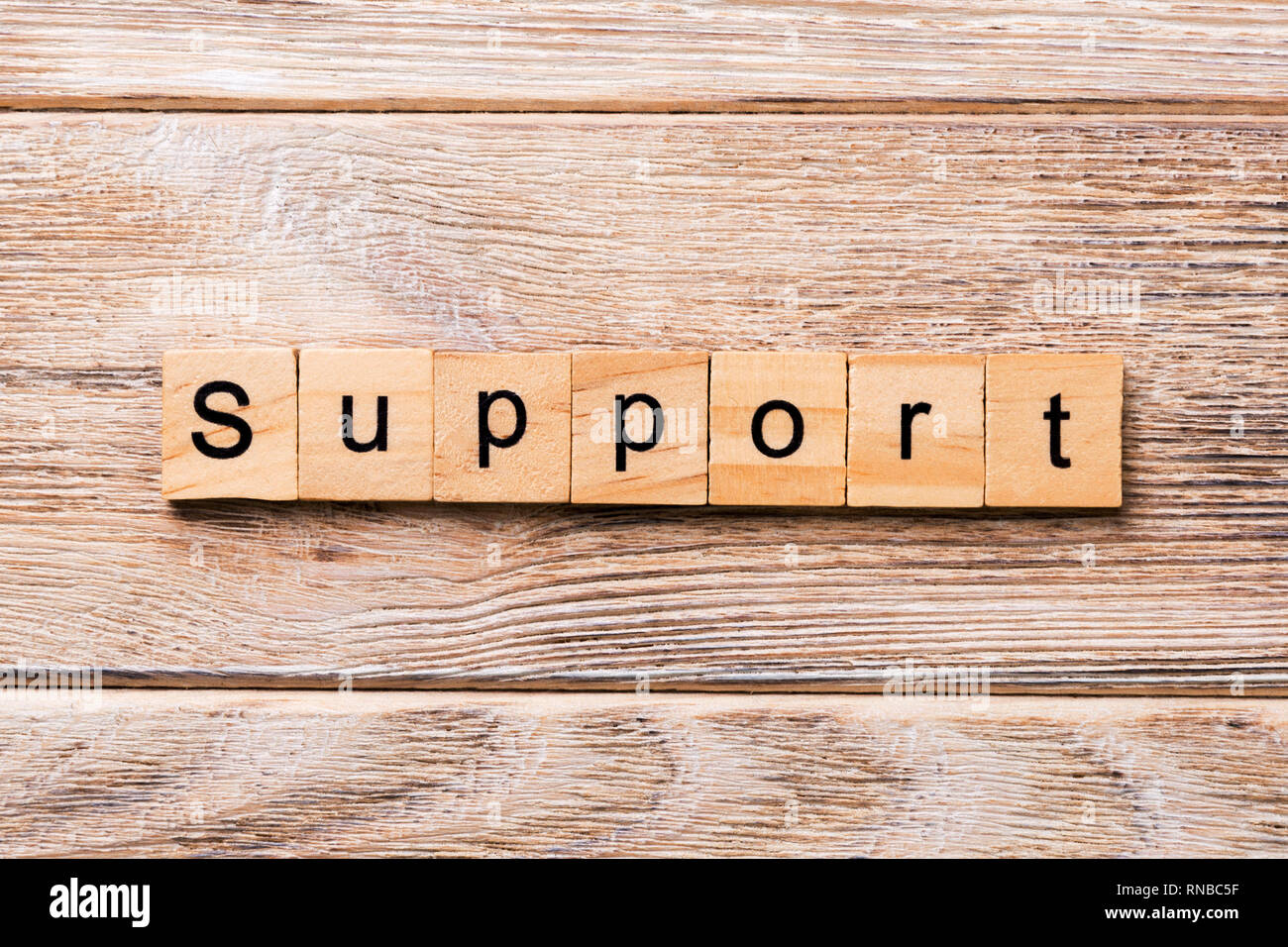 Support word written on wood block. Support text on wooden table for ...