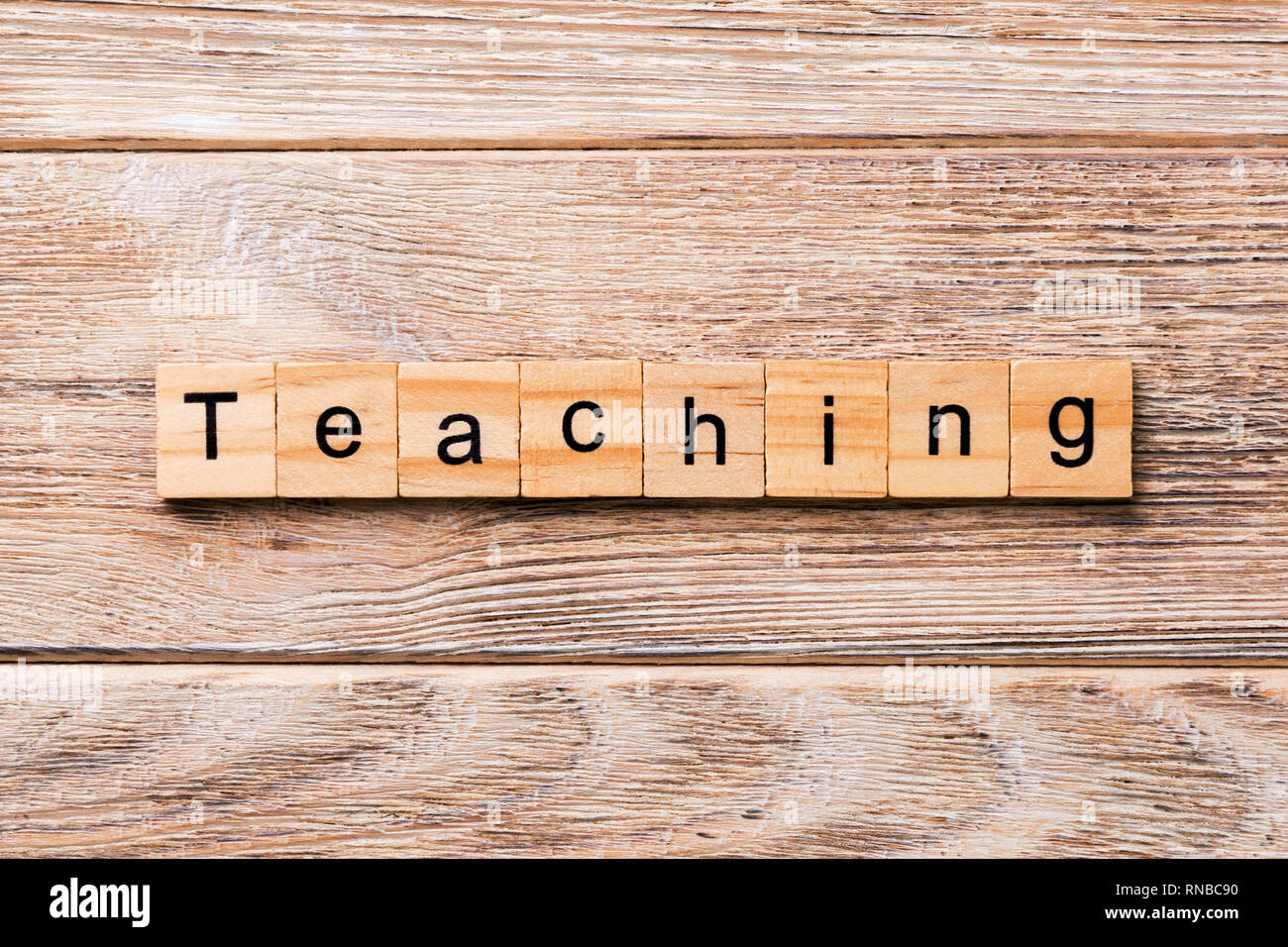 TEACHING word written on wood block. TEACHING text on wooden table for ...