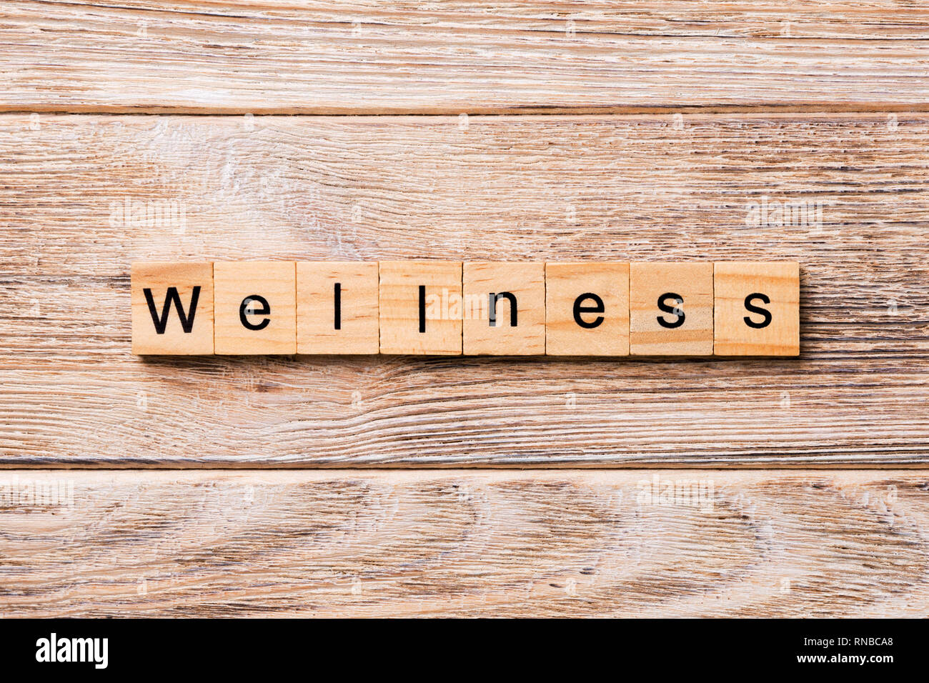 Wellness word written on wood block. Wellness text on wooden table for ...