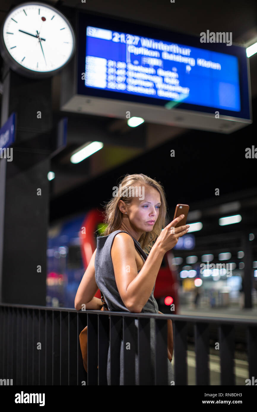 Pretty, young female commuter waiting for her daily train in a modern ...