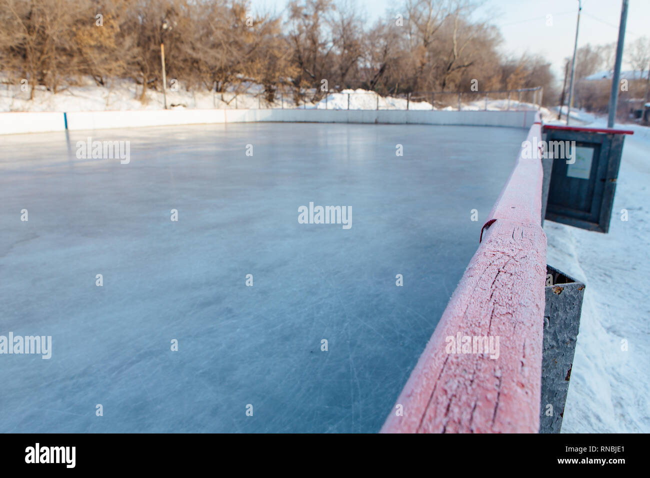 Outdoor empty skating and ice hockery rink with frozen covered with ice ...