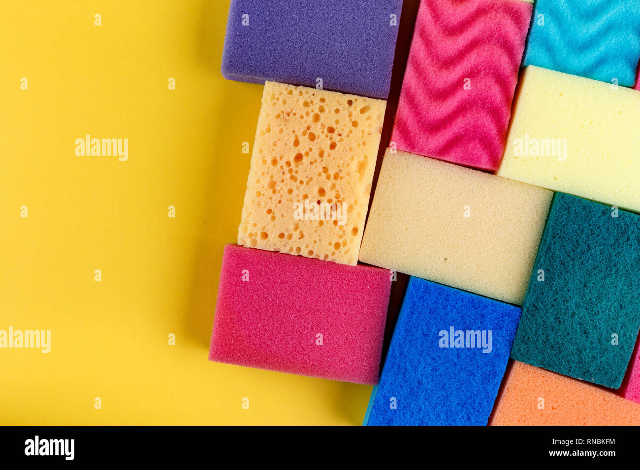 Many multicolored sponge for washing dishes on a yellow background ...