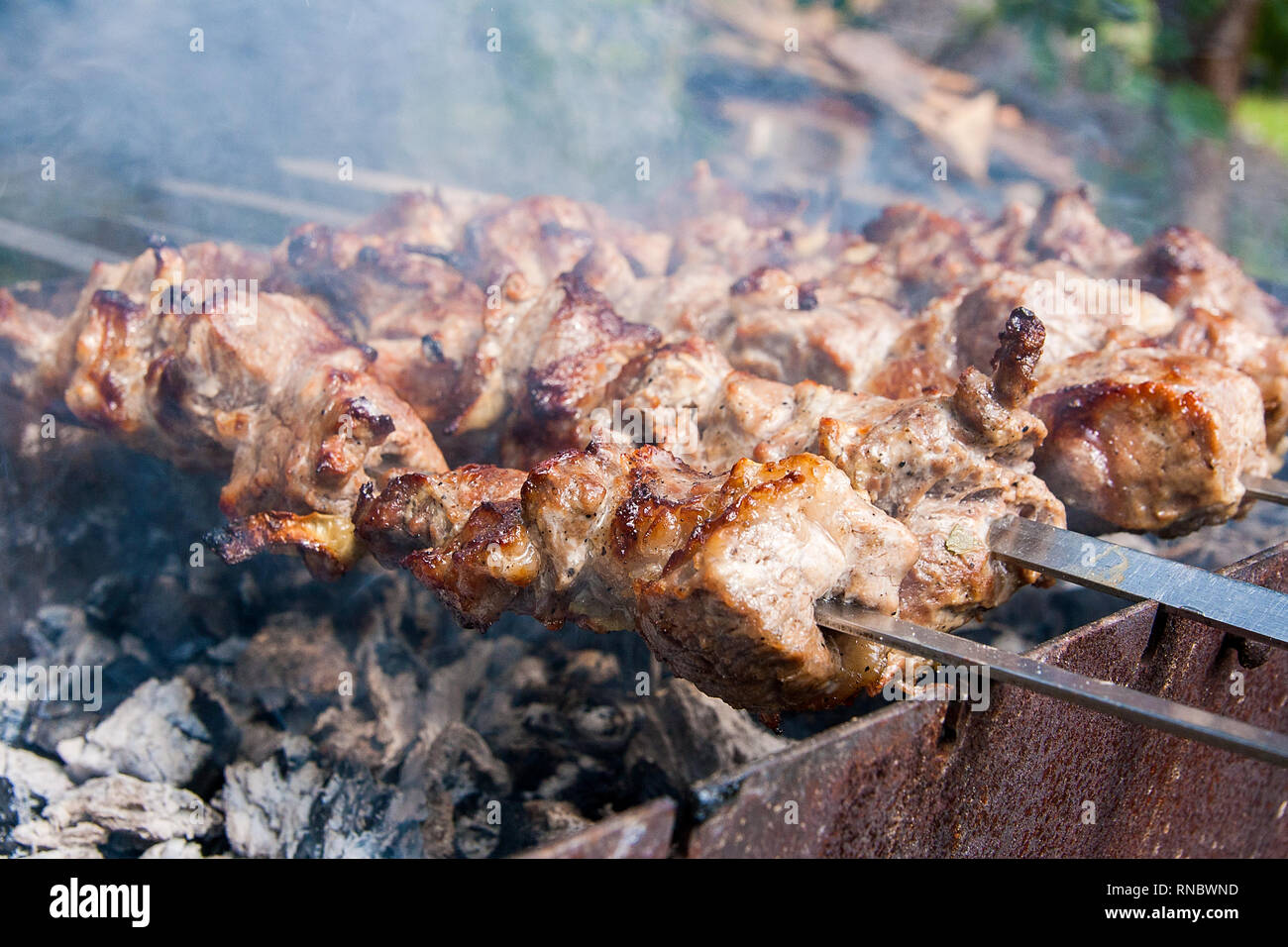 Grilled kebab cooking on metal skewer. Shashlik made of cubes of meat ...