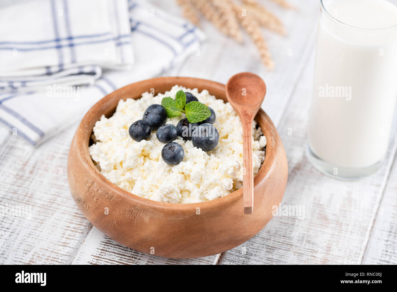 Tvorog or cottage cheese in wooden bowl, bottle of cow milk and wheat ...