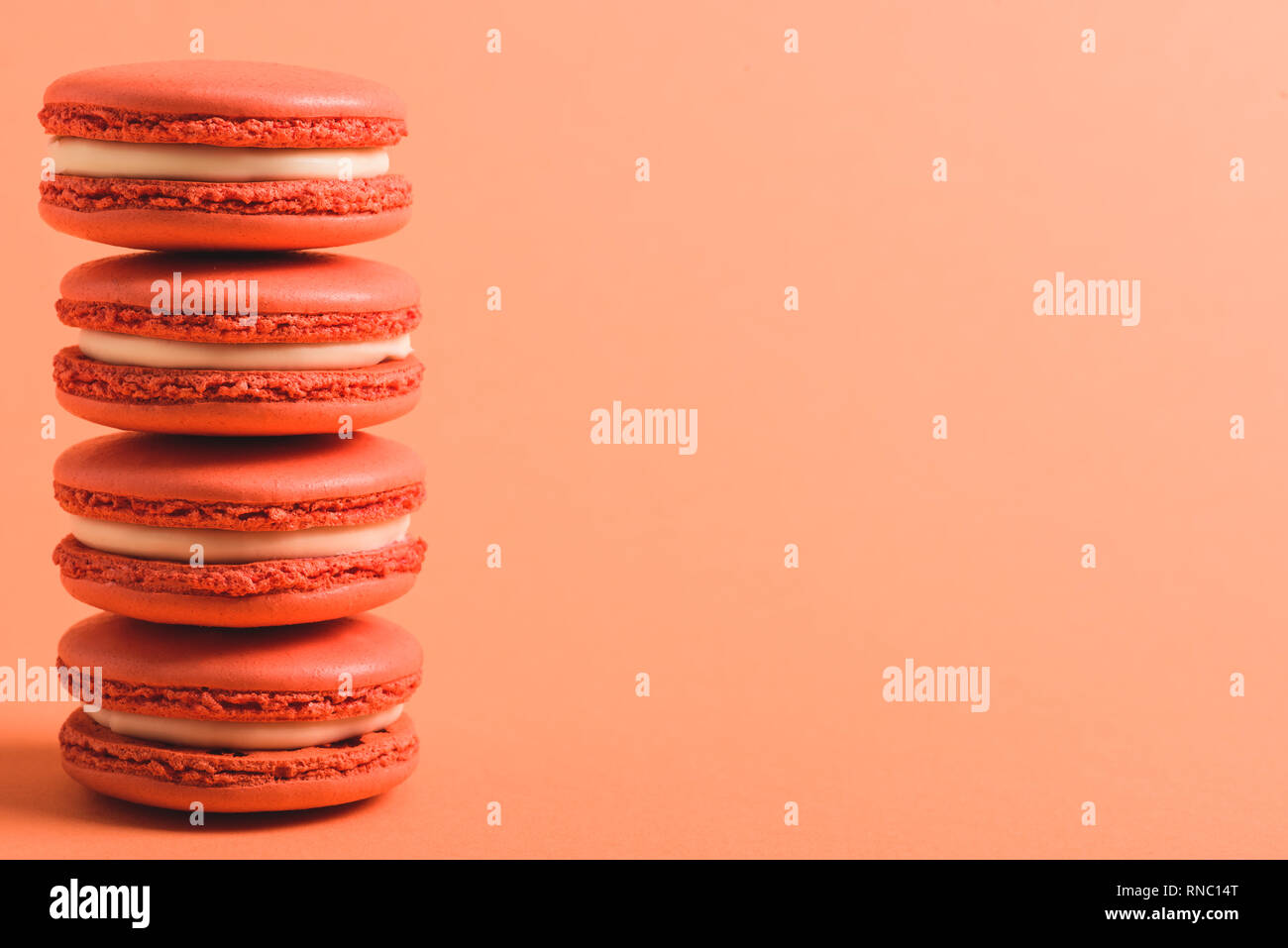 stack of coral macarons on coral background with copy space, color of ...