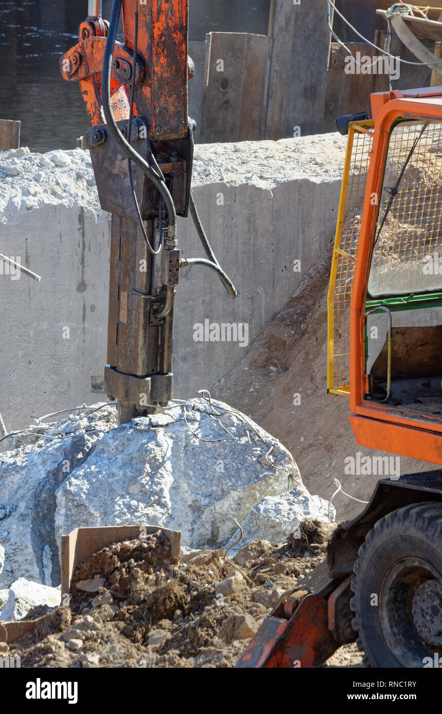Demolition excavator hydraulic hammer resting between two pieces of ...