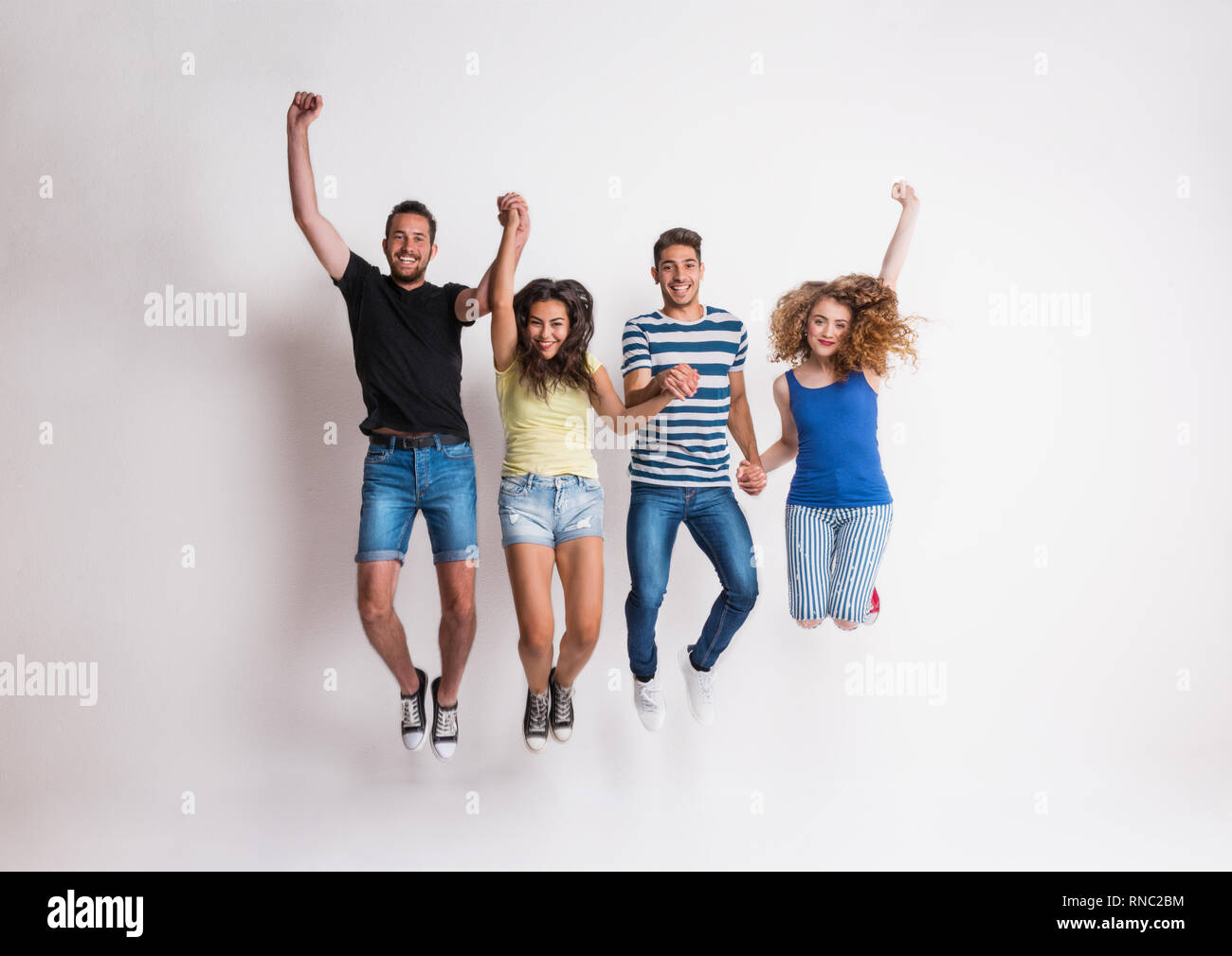 Portrait of joyful young group of friends jumping in a studio Stock ...