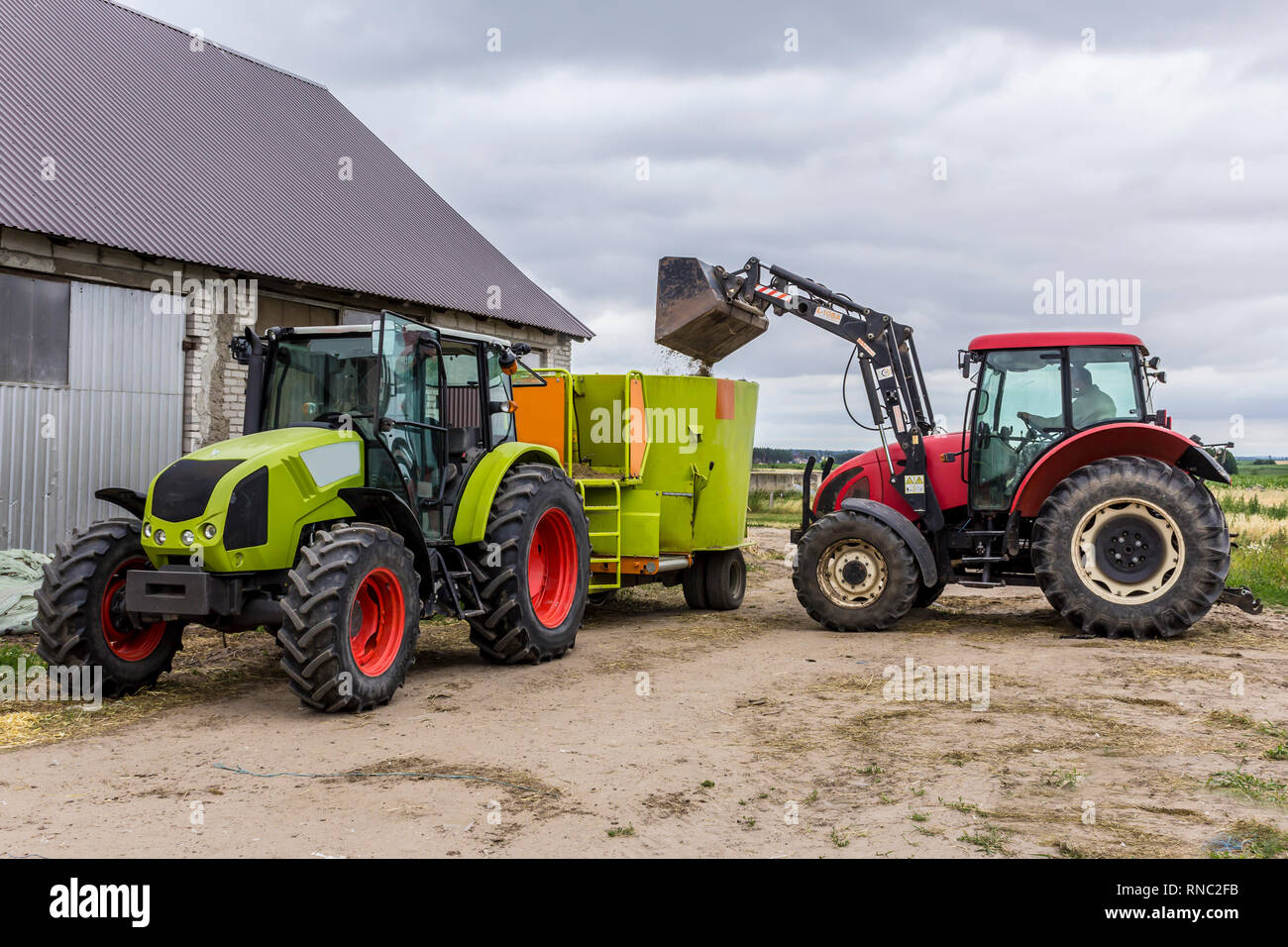 Tractor with front end loader loads the food into a distributor of ...